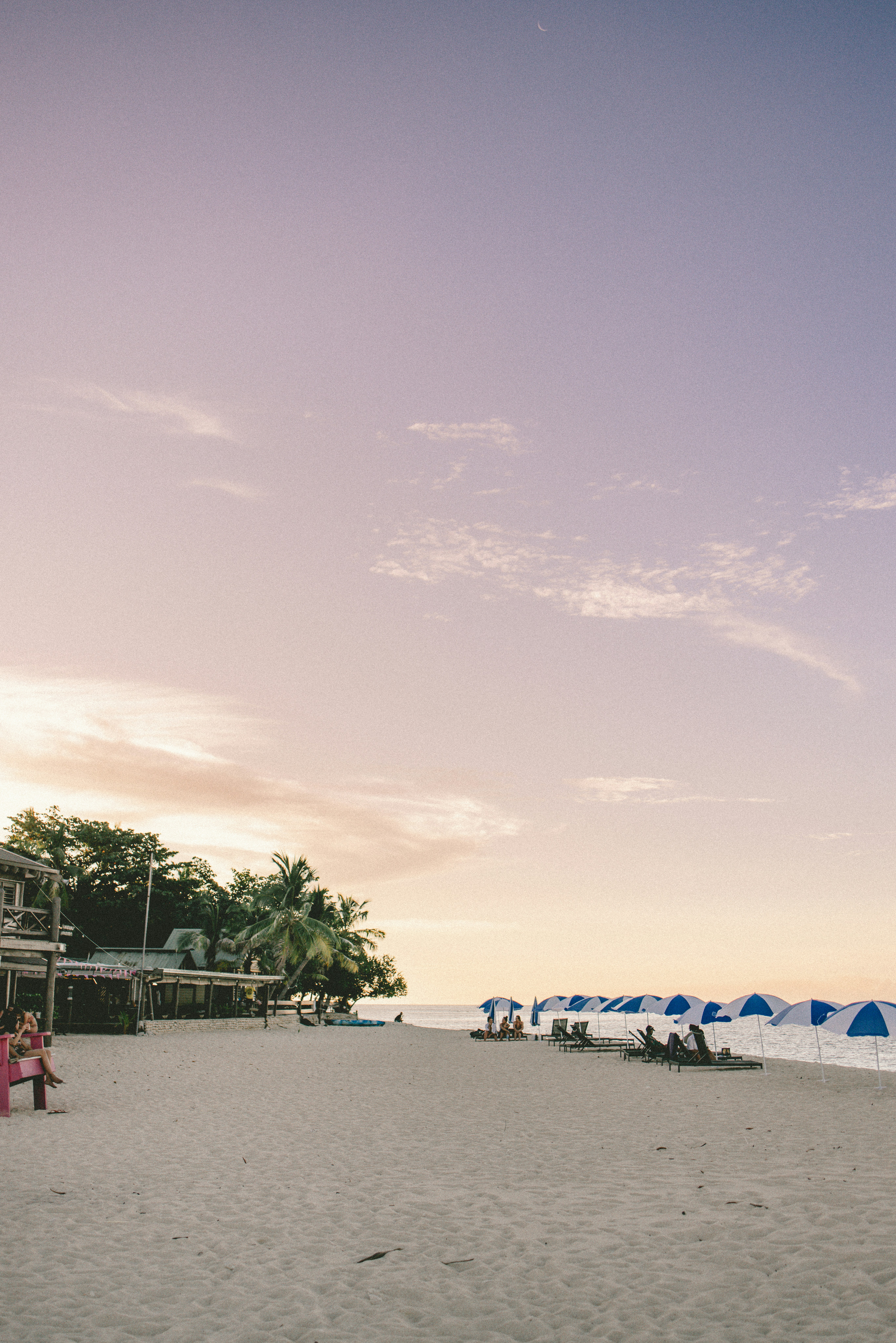 A group of people sitting on top of a sandy beach photo – Free ...