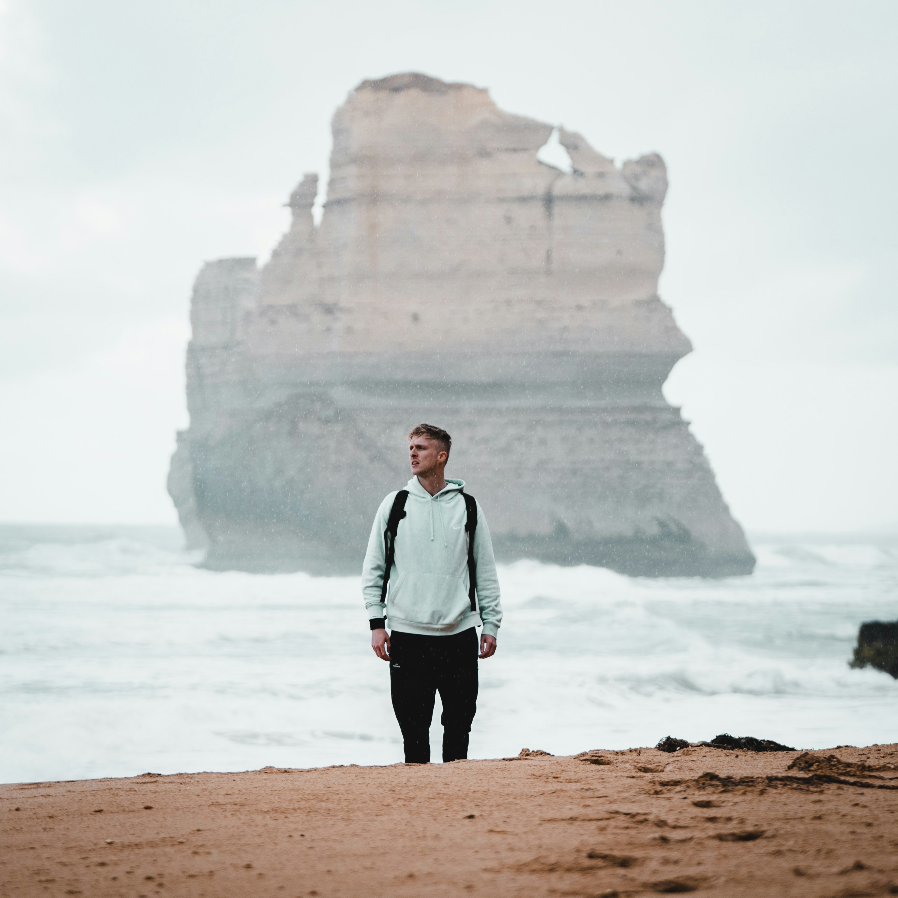 A man standing on a beach next to the ocean photo – Free Male Image on ...