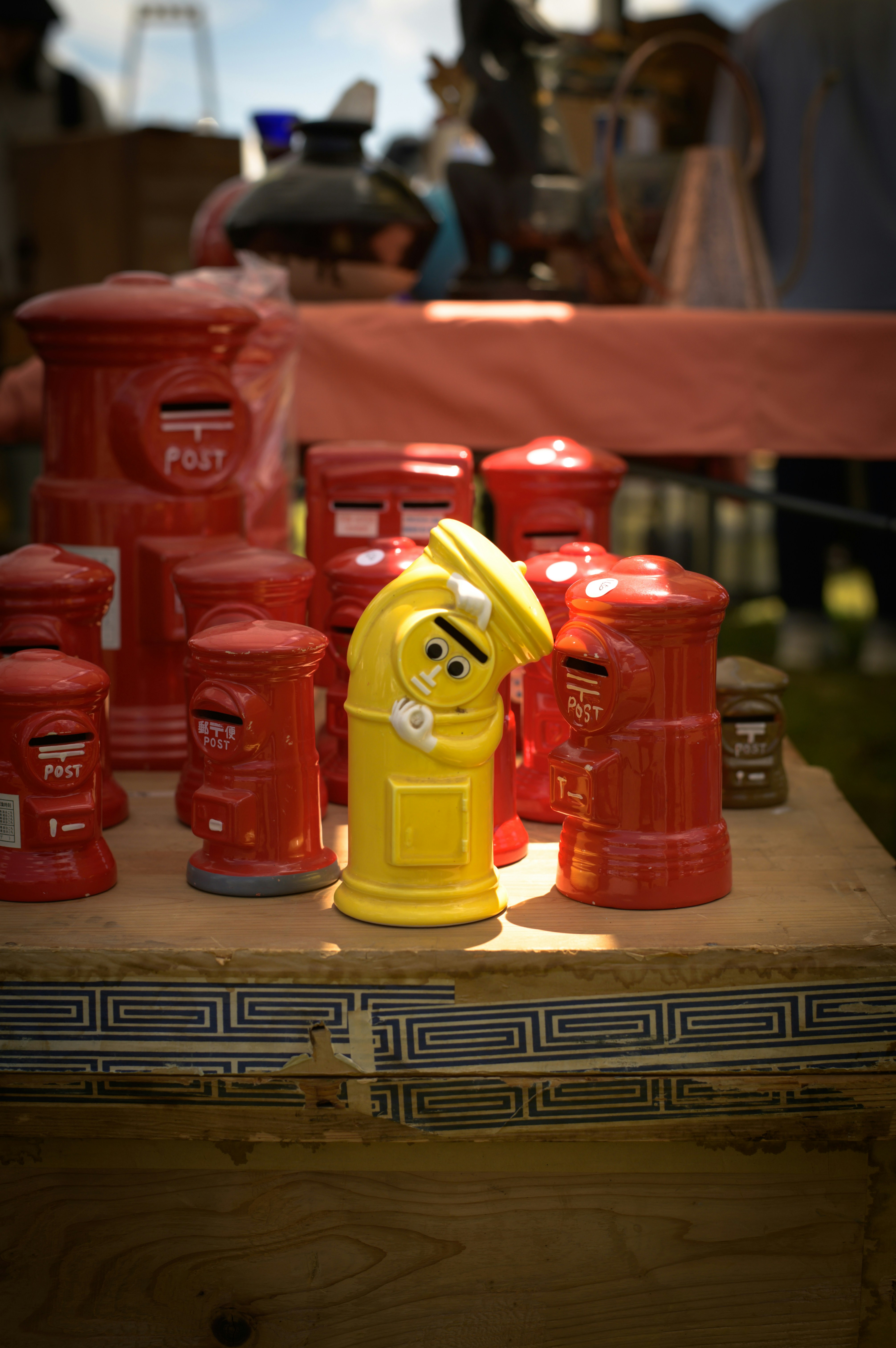 Yellow Fireman Figurine Among Red Mailboxes on a Rustic Table