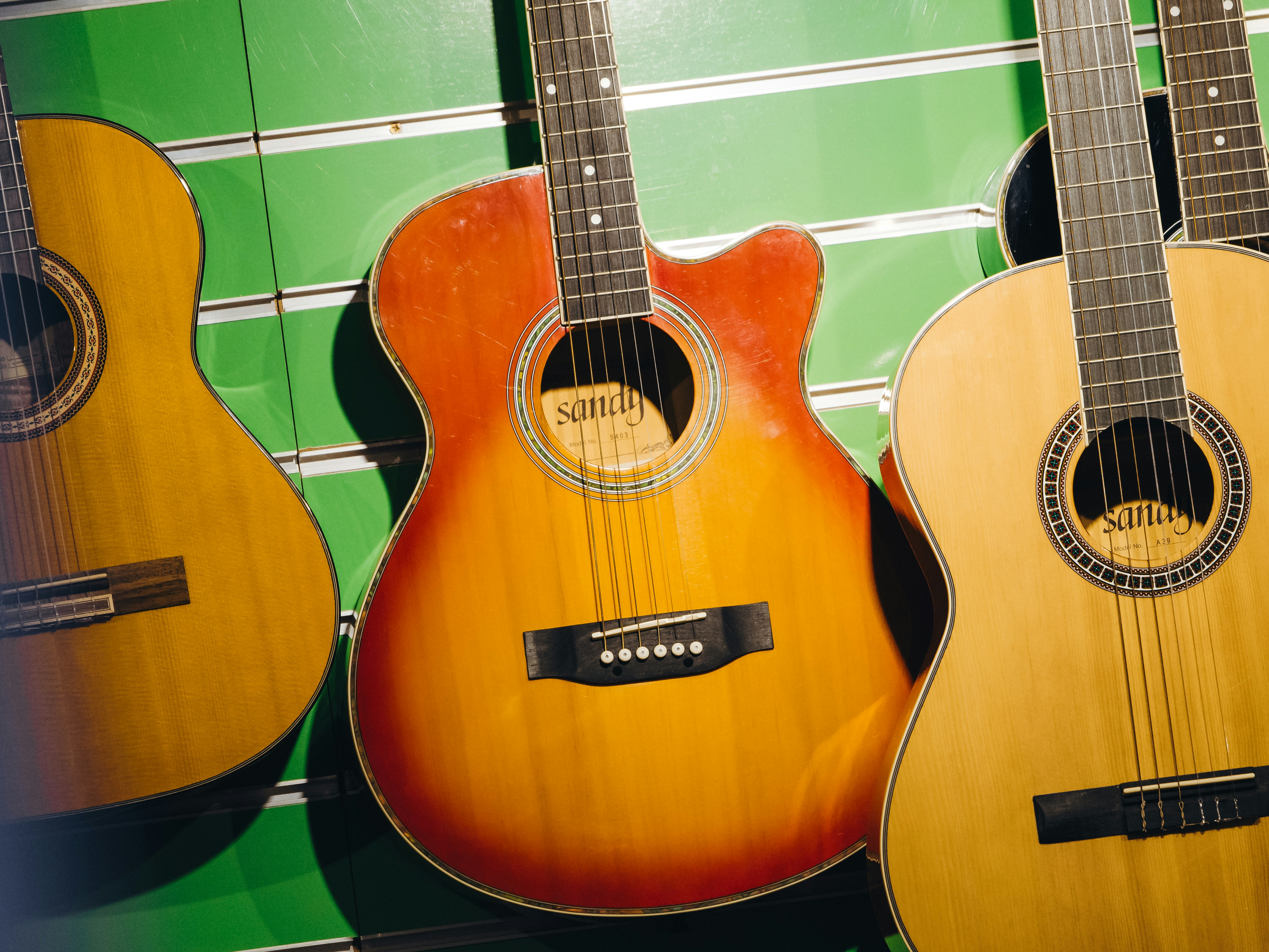 Three guitars are lined up against a green wall photo – Free Decoration ...