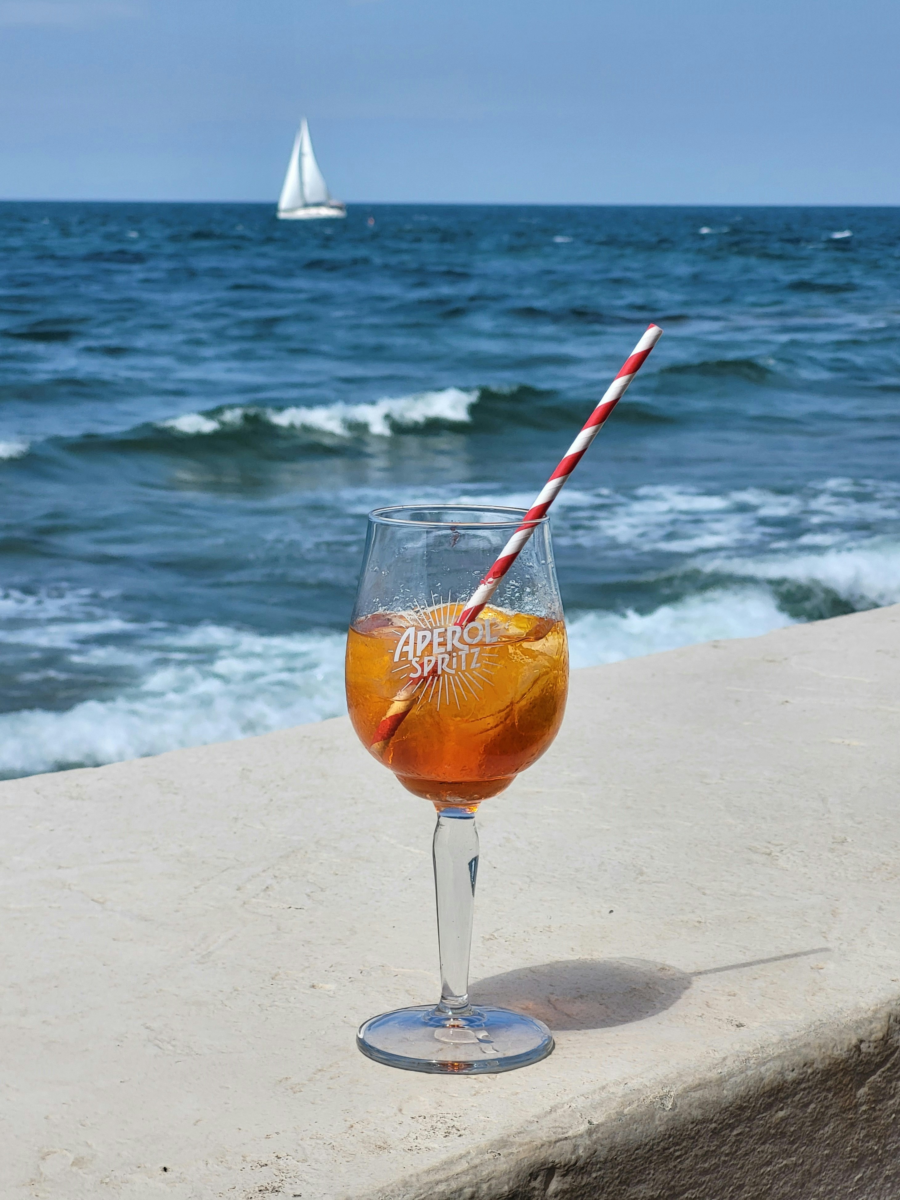 A glass of wine sitting on a ledge next to the ocean photo – Free ...