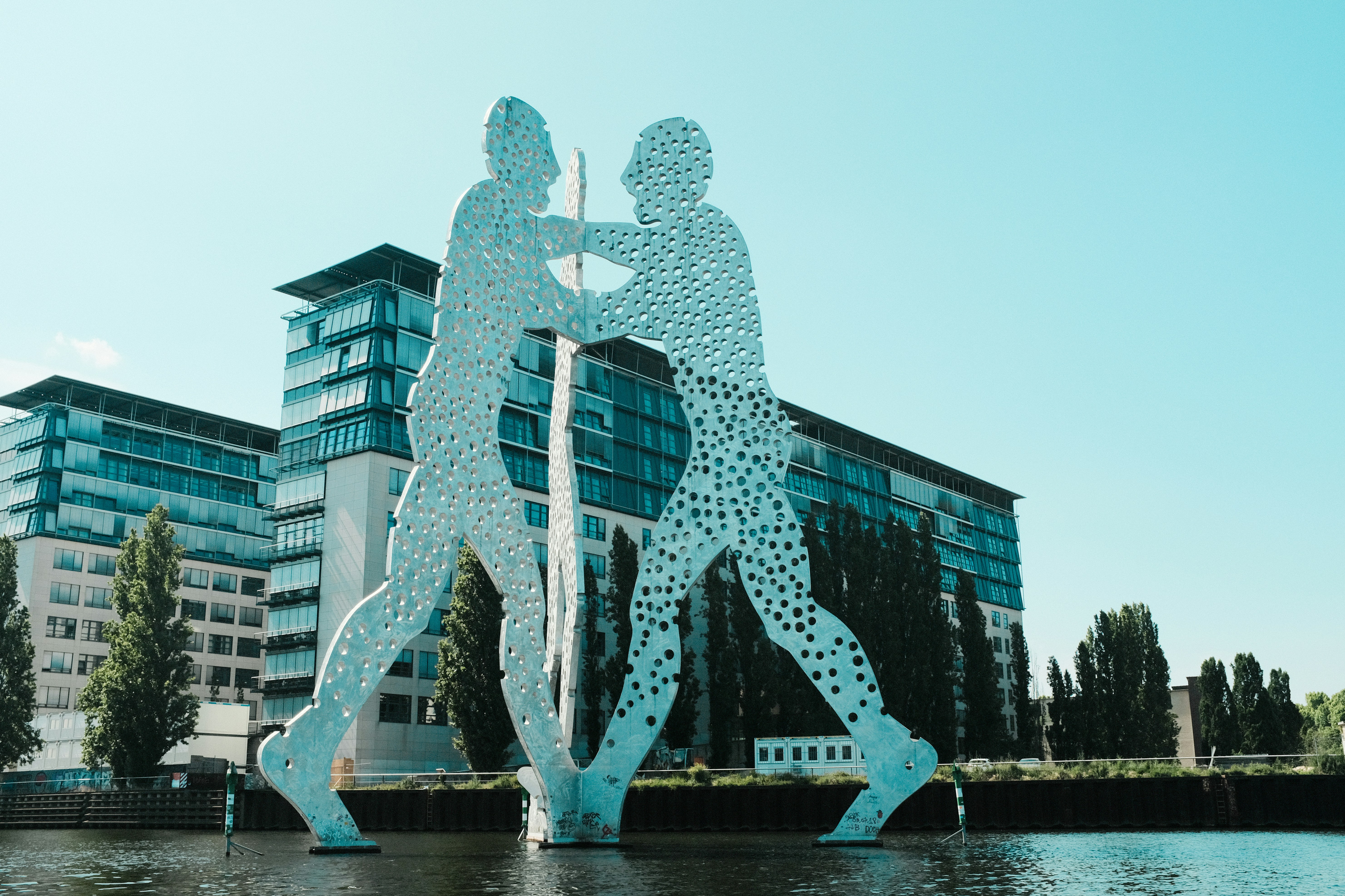 Duet of Perforated Steel Silhouettes Over a Reflective Canal