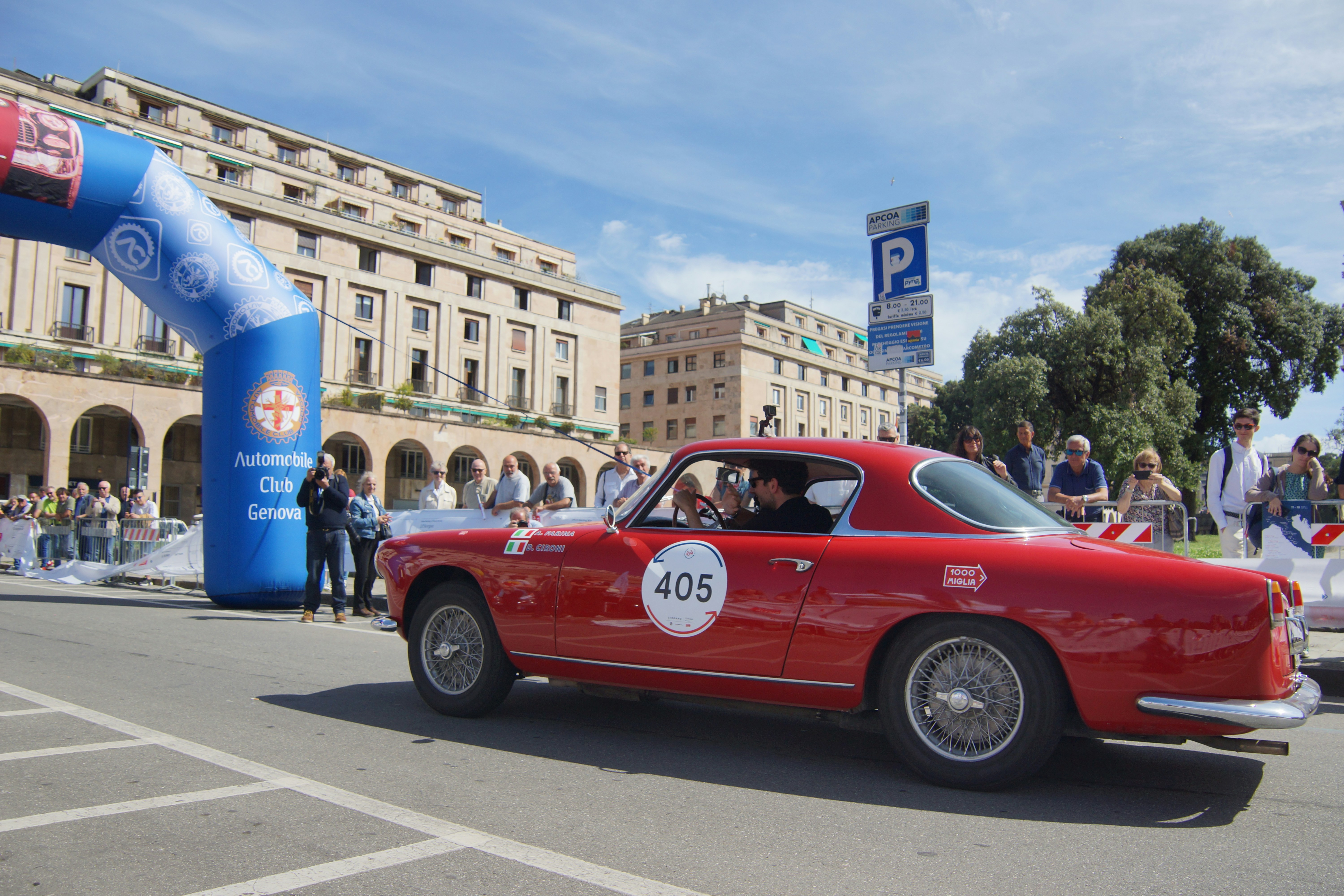 A red car driving down a street next to a tall building photo – Free ...