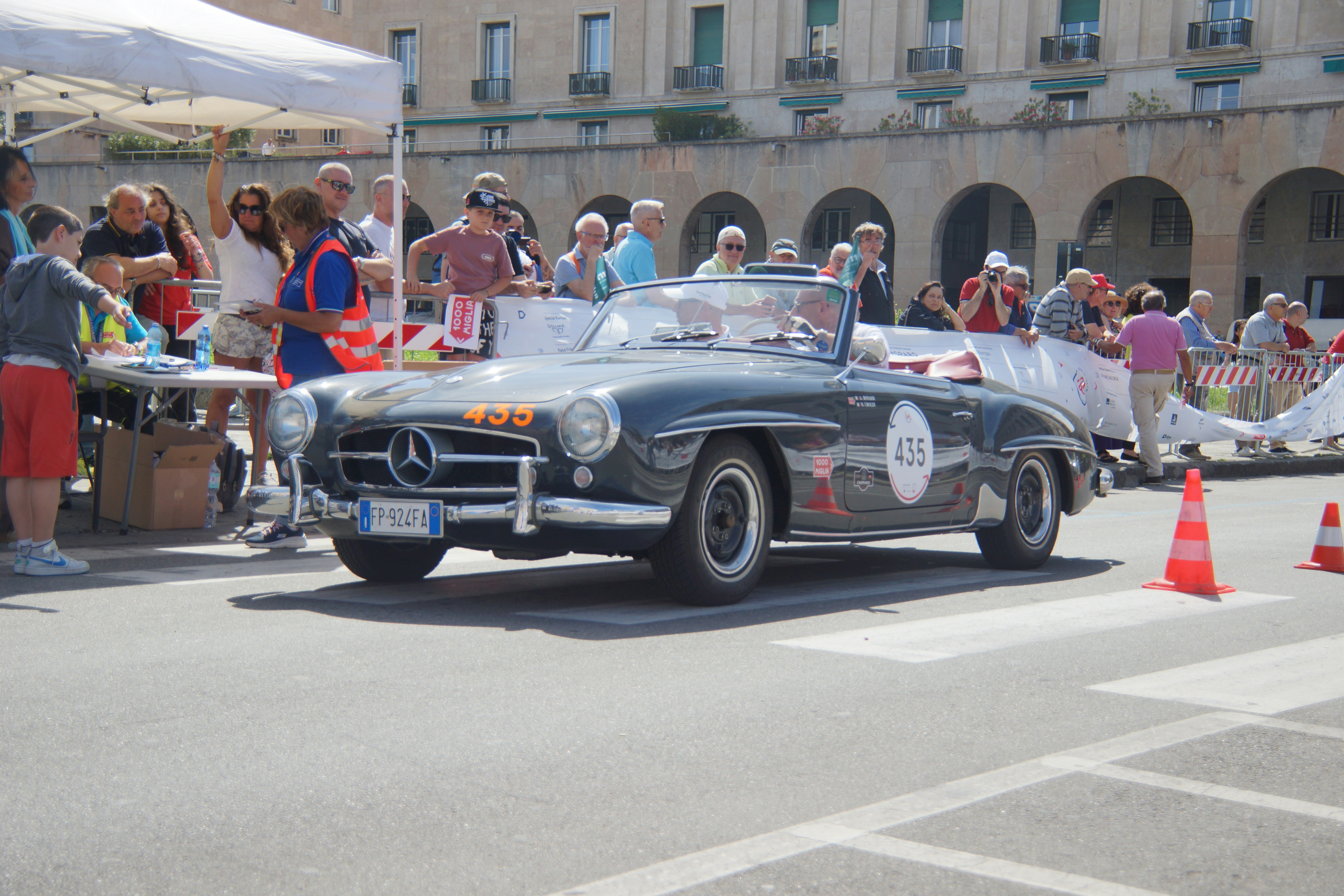 A car driving down a street past a crowd of people photo – Free Genova ...