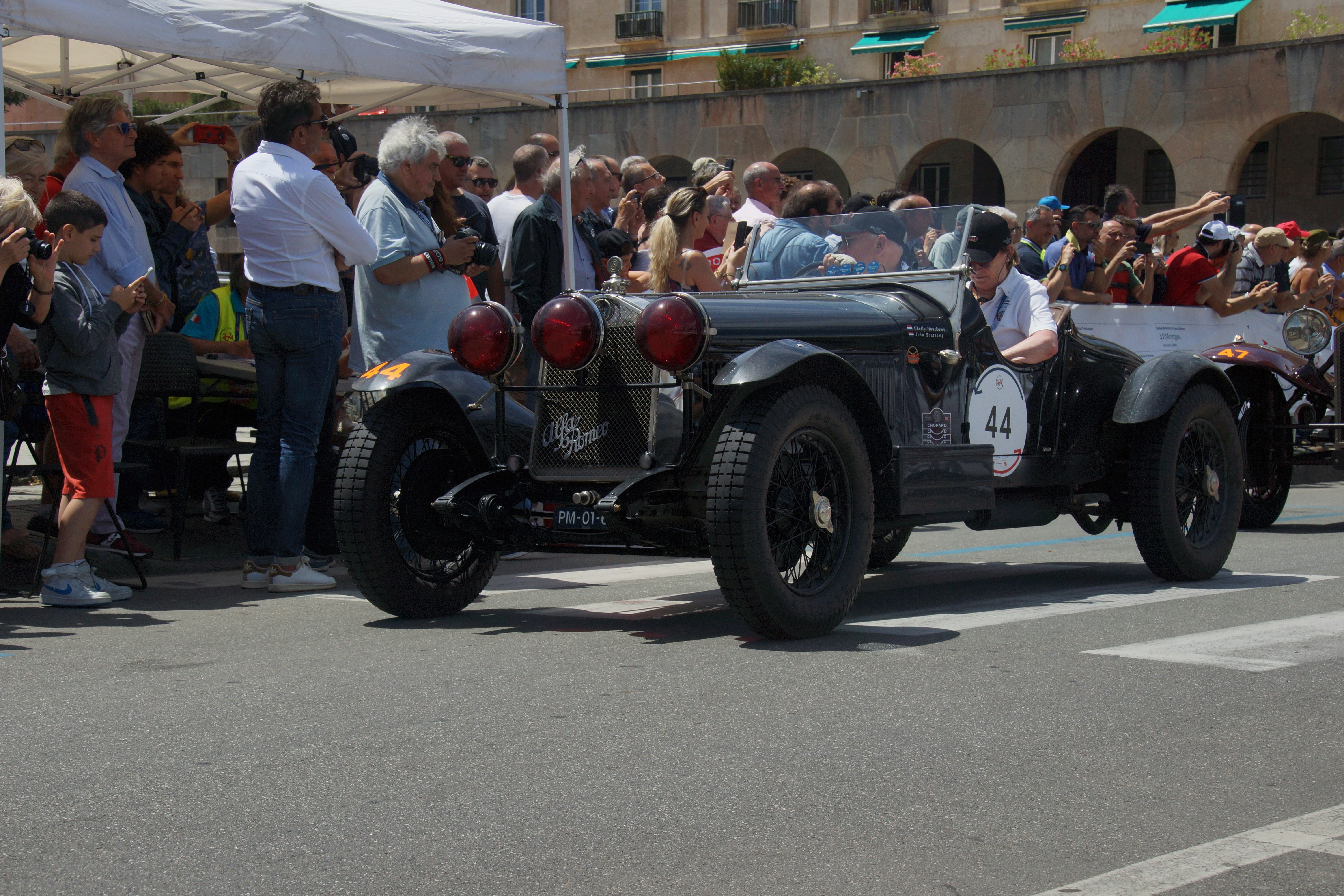 A vintage car driving down a street past a crowd of people photo – Free ...