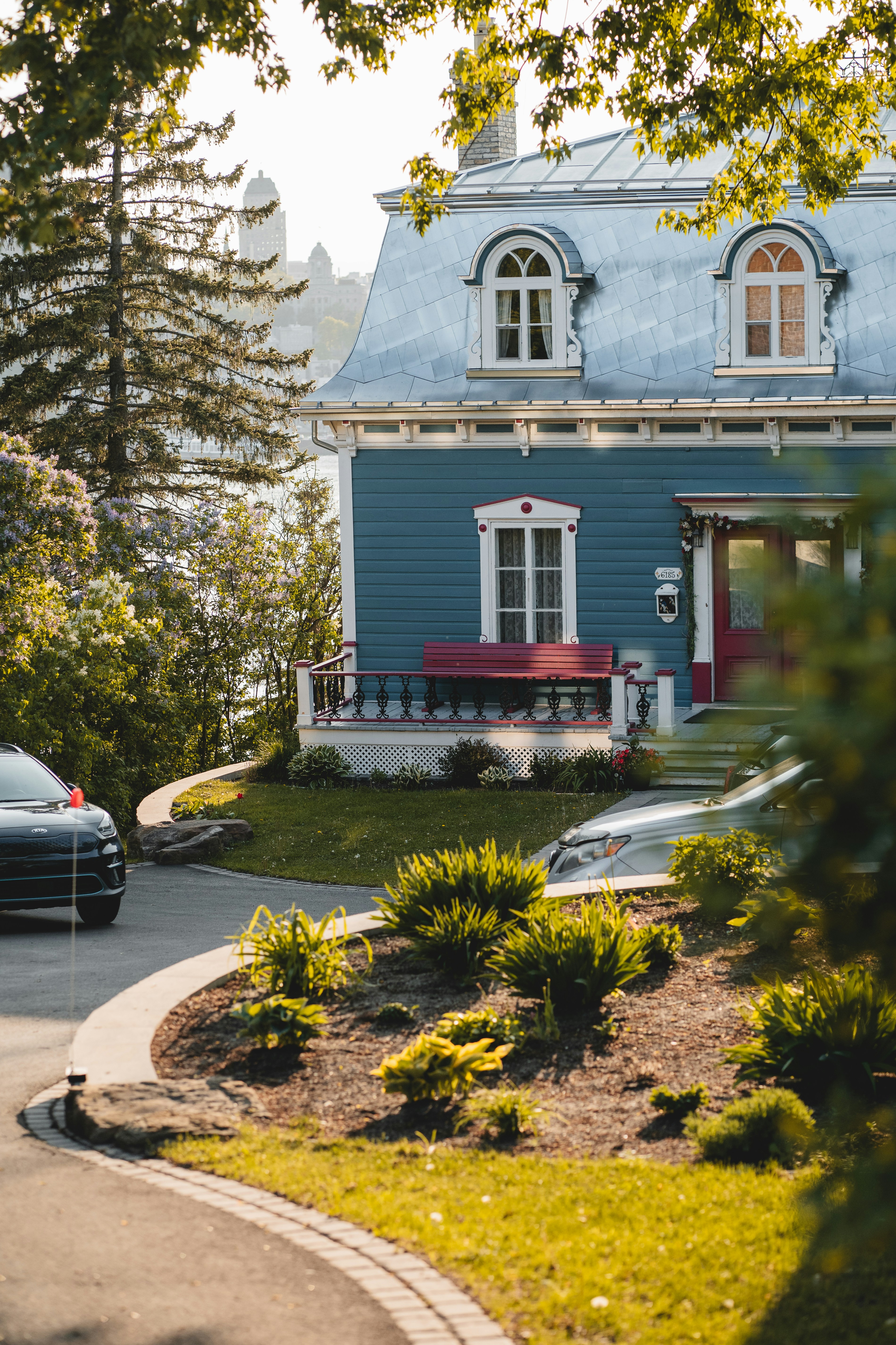 Sunlit Blue Victorian Cottage Framed by a Curved Driveway and a Crimson Bench