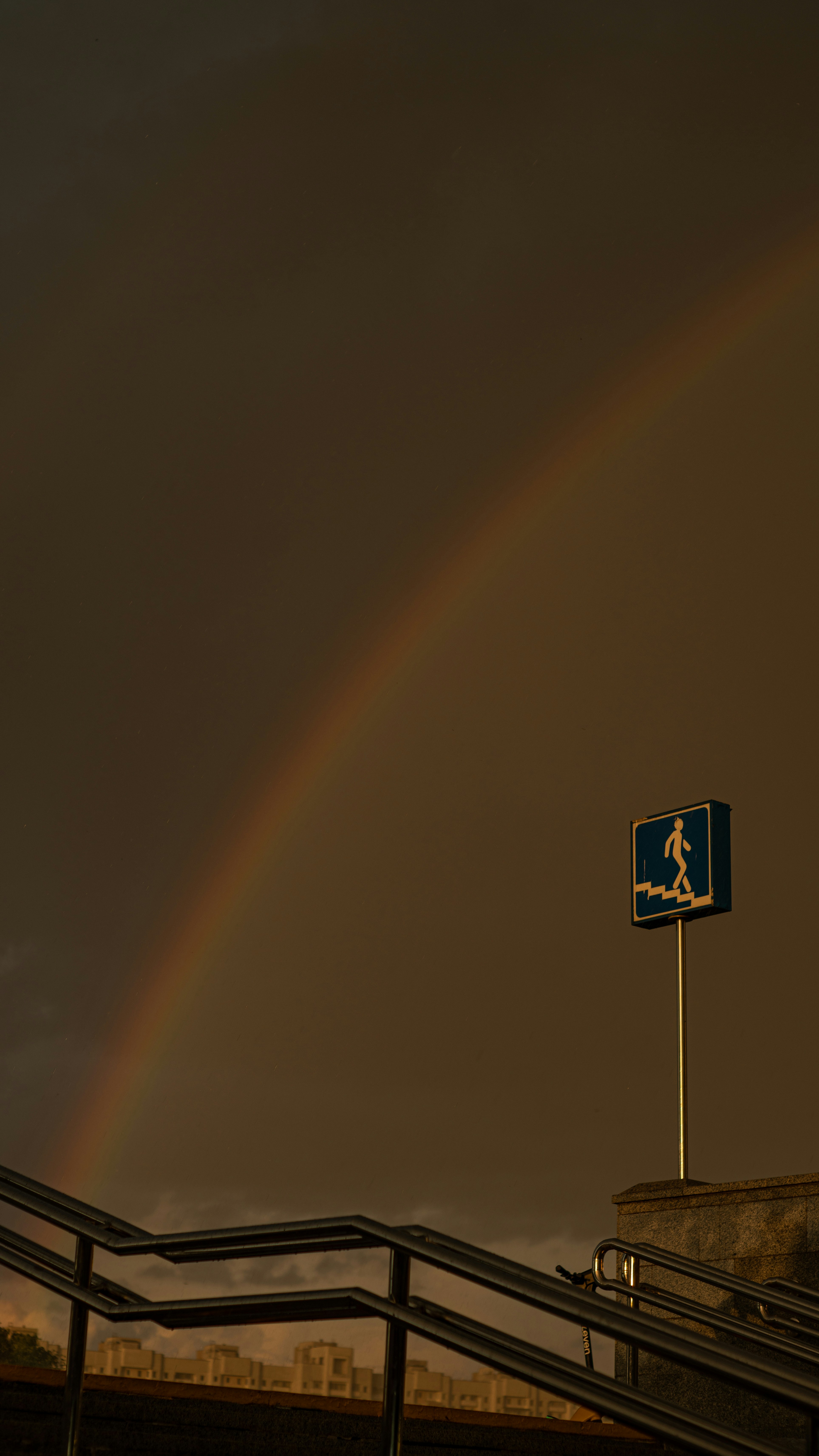Rainbow Arc Over Urban Stairs Beneath a Quiet Signpost