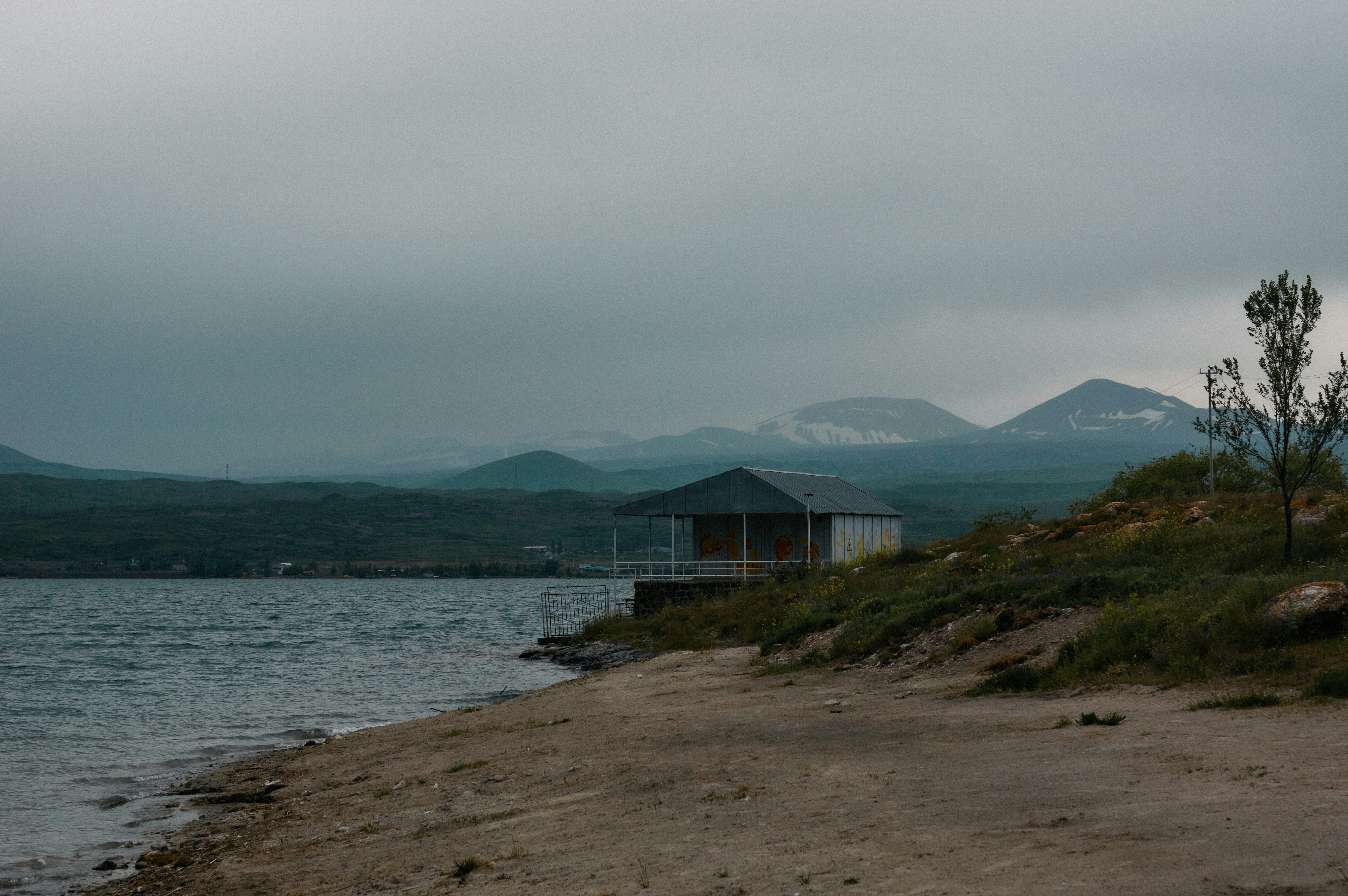 Coastal Cabin at Dusk: Quiet Dunes and Distant Peaks