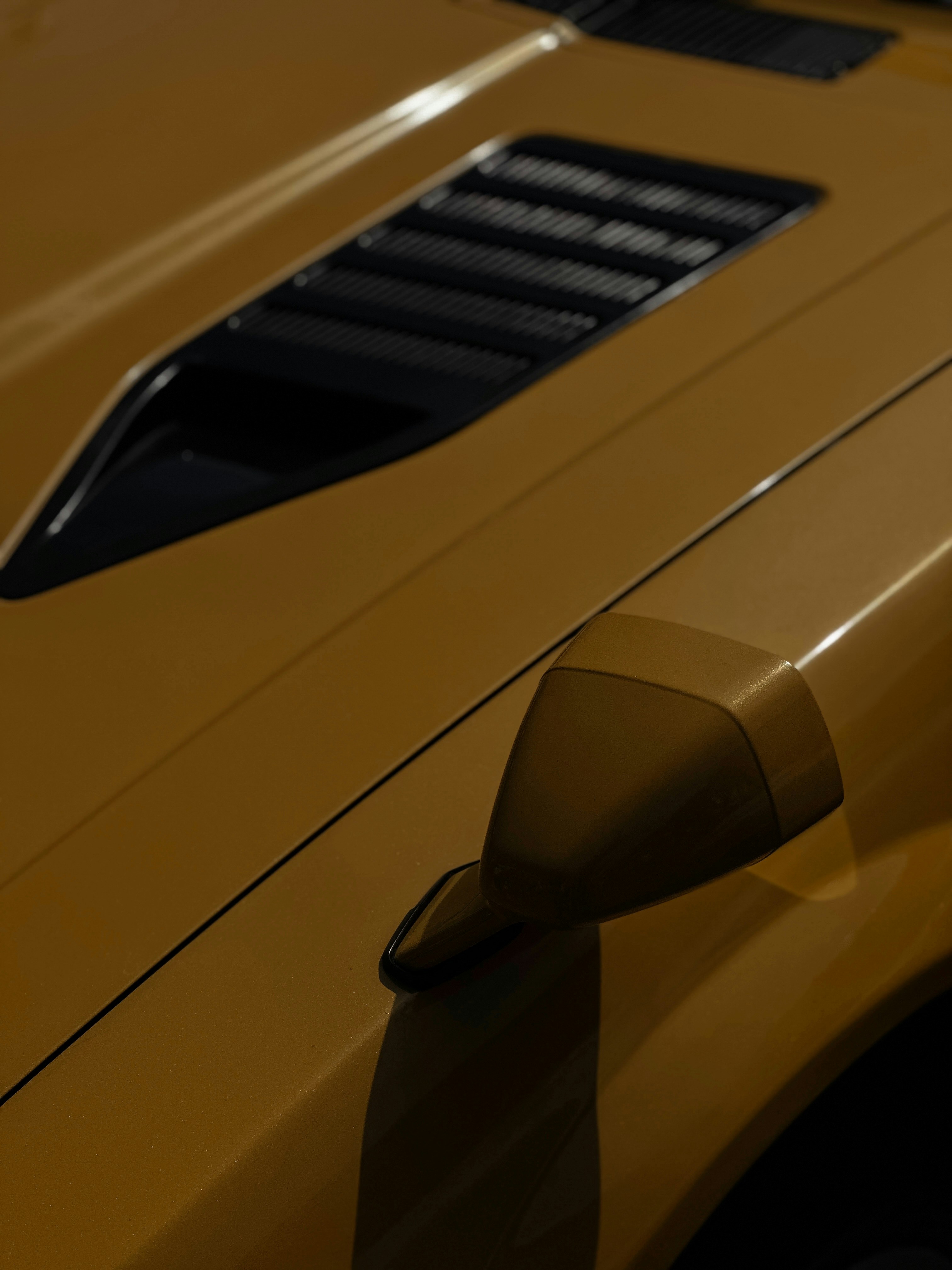 Amber Precision: Night Close-Up of a Classic Car's Hood Vent and Mirror