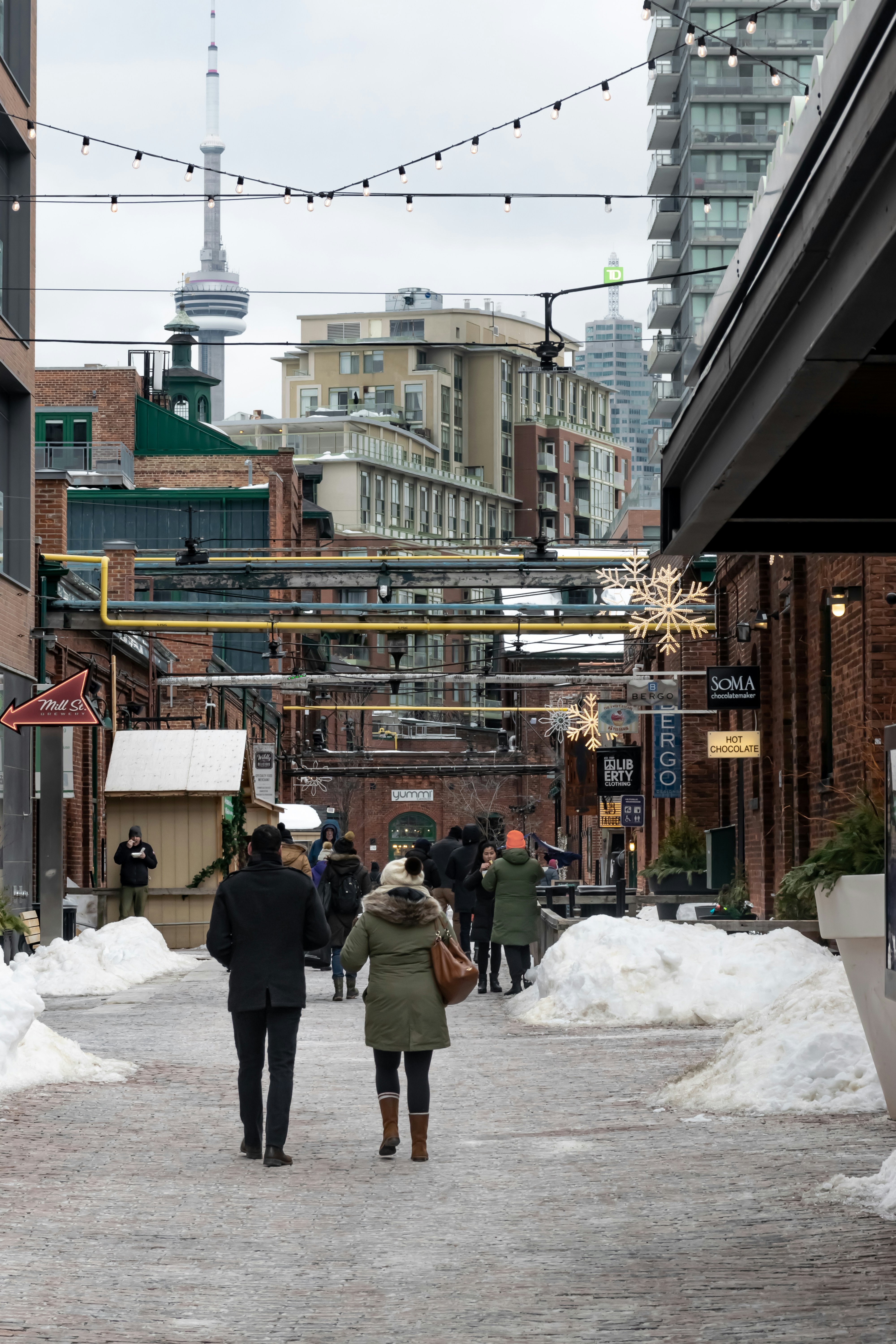 Snow-Laced Toronto Alley: Pedestrians, Lights, and the Tower in the Distance