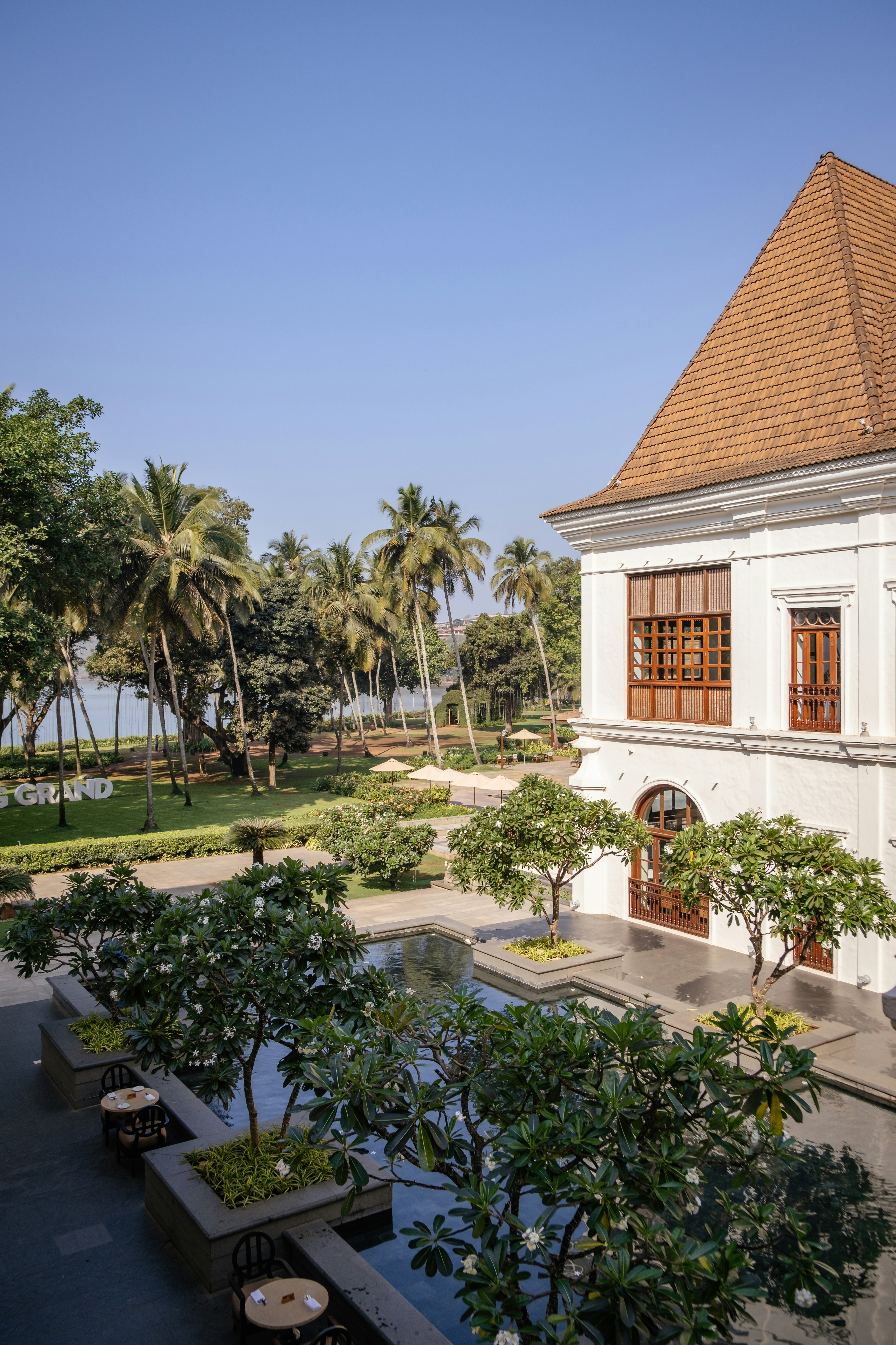 Sunlit Colonial Villa Framing a Palm-Lined Courtyard by the Pool
