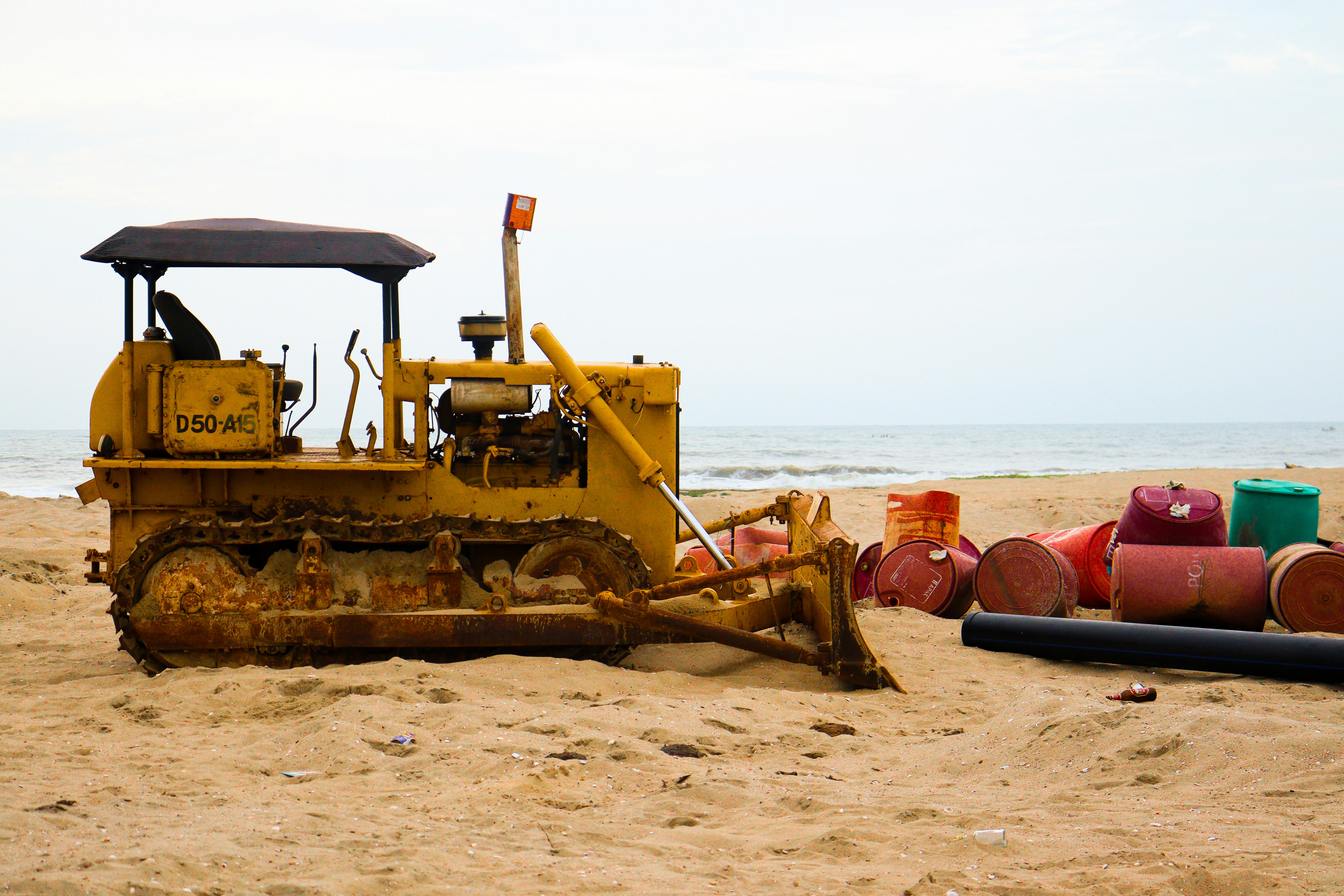 A yellow bulldozer sitting on top of a sandy beach photo – Free Machine ...