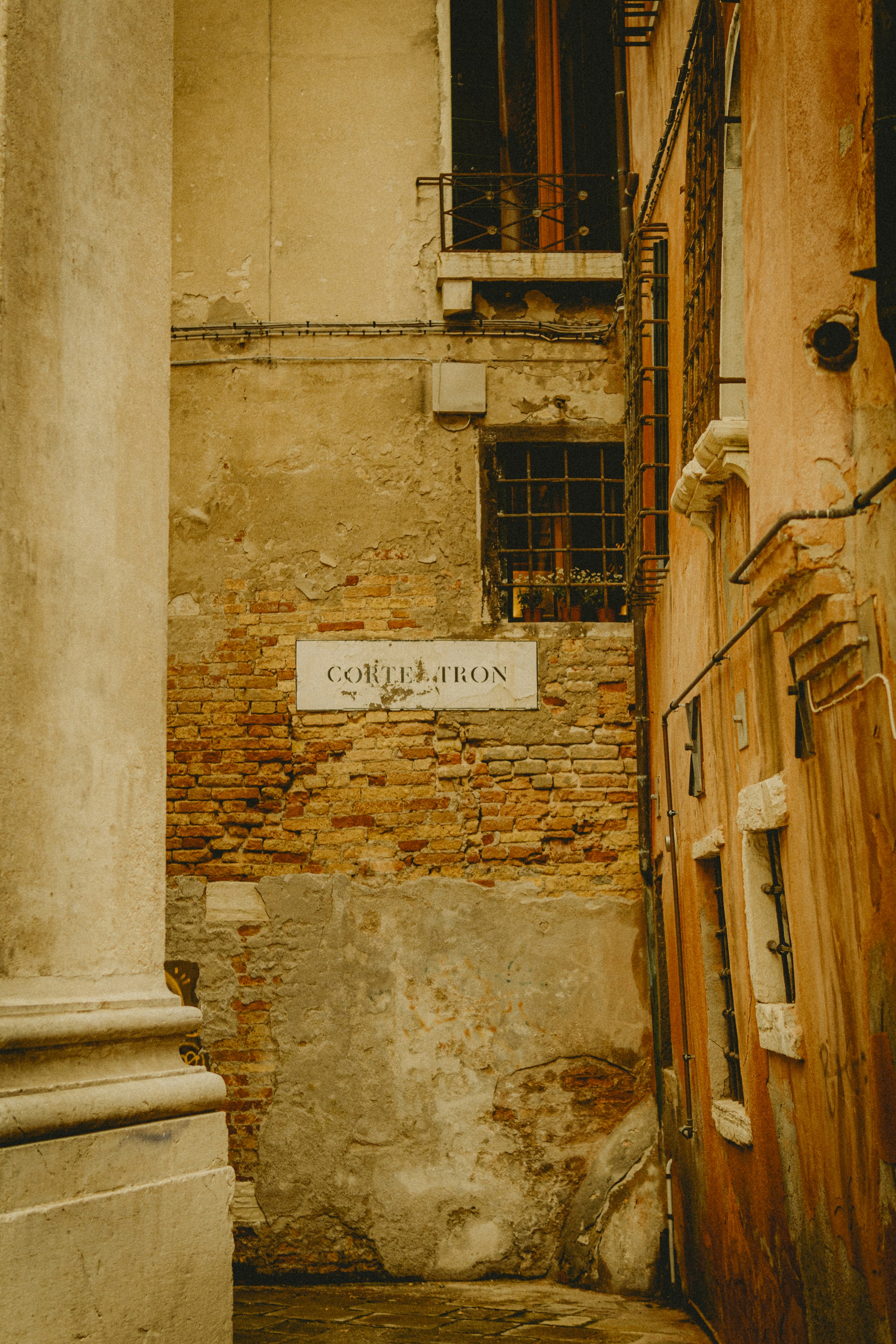 Amber Alleyways: Weathered Brick, Stone Column, and a Faded Sign
