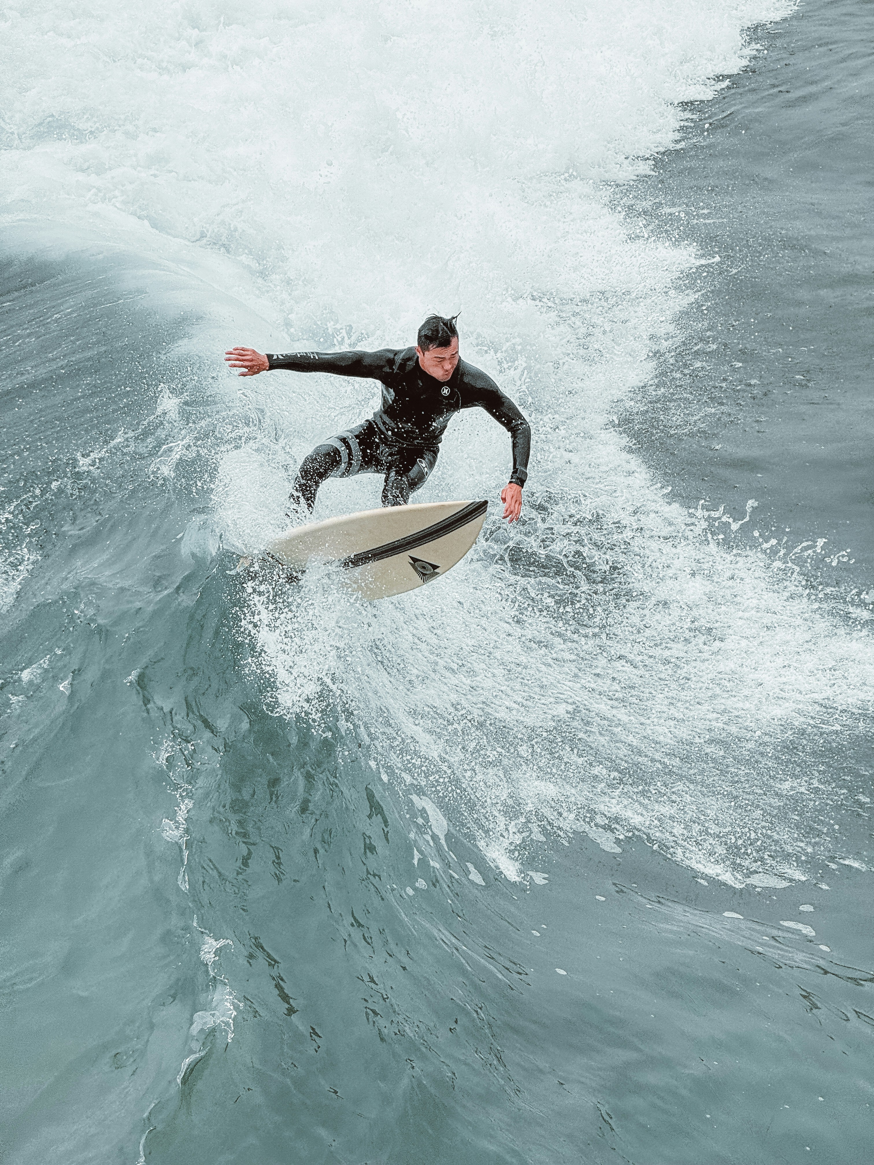 Crescent of Foam: Surfer Carves a Moment Across a Turbulent Wave