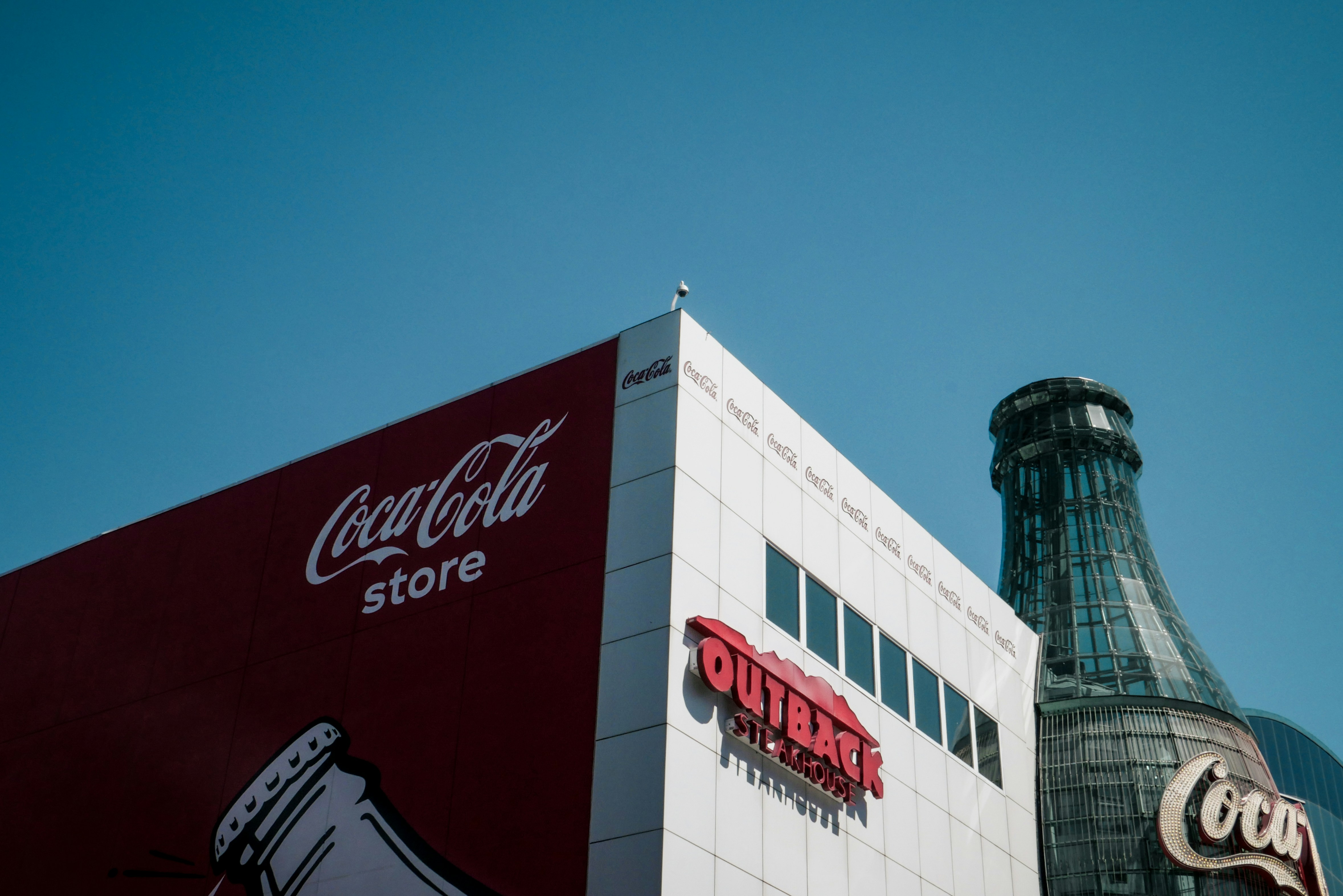 A coca - cola store and a coca - cola bottle on the side of a photo ...