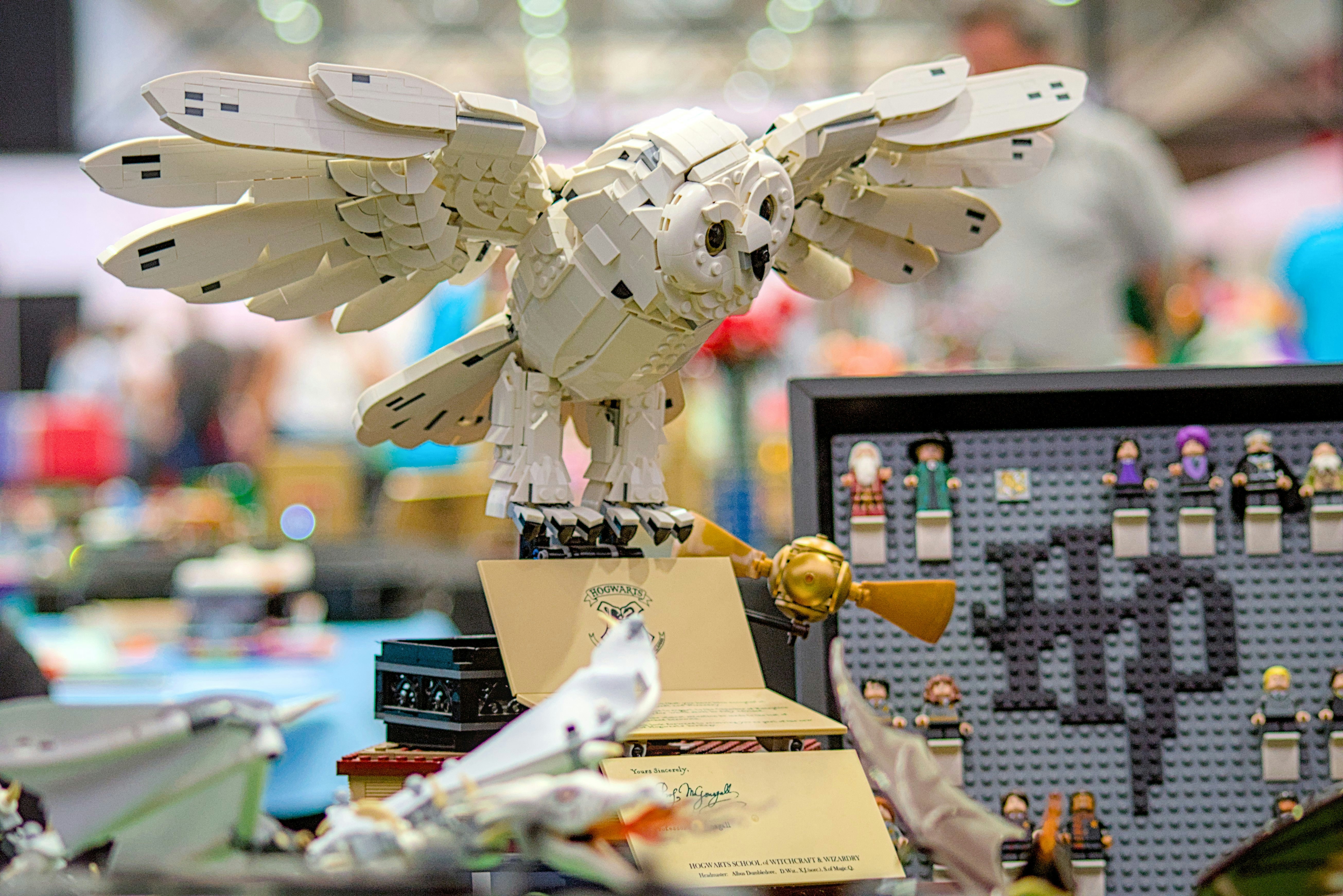 Winged LEGO Owl on a Display Pedestal at a Bustling Hobby Show