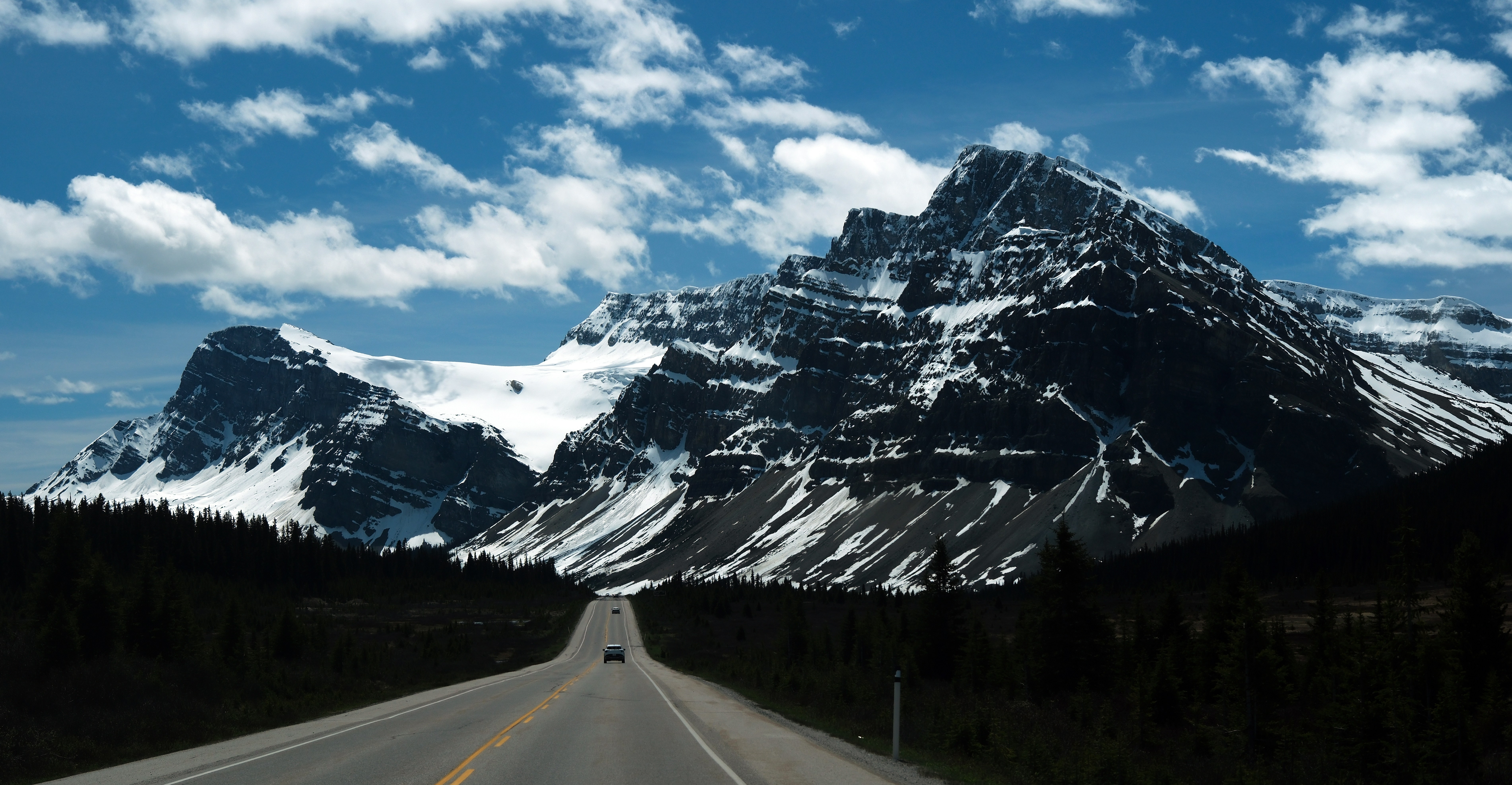 A car driving down a road with a mountain in the background photo ...