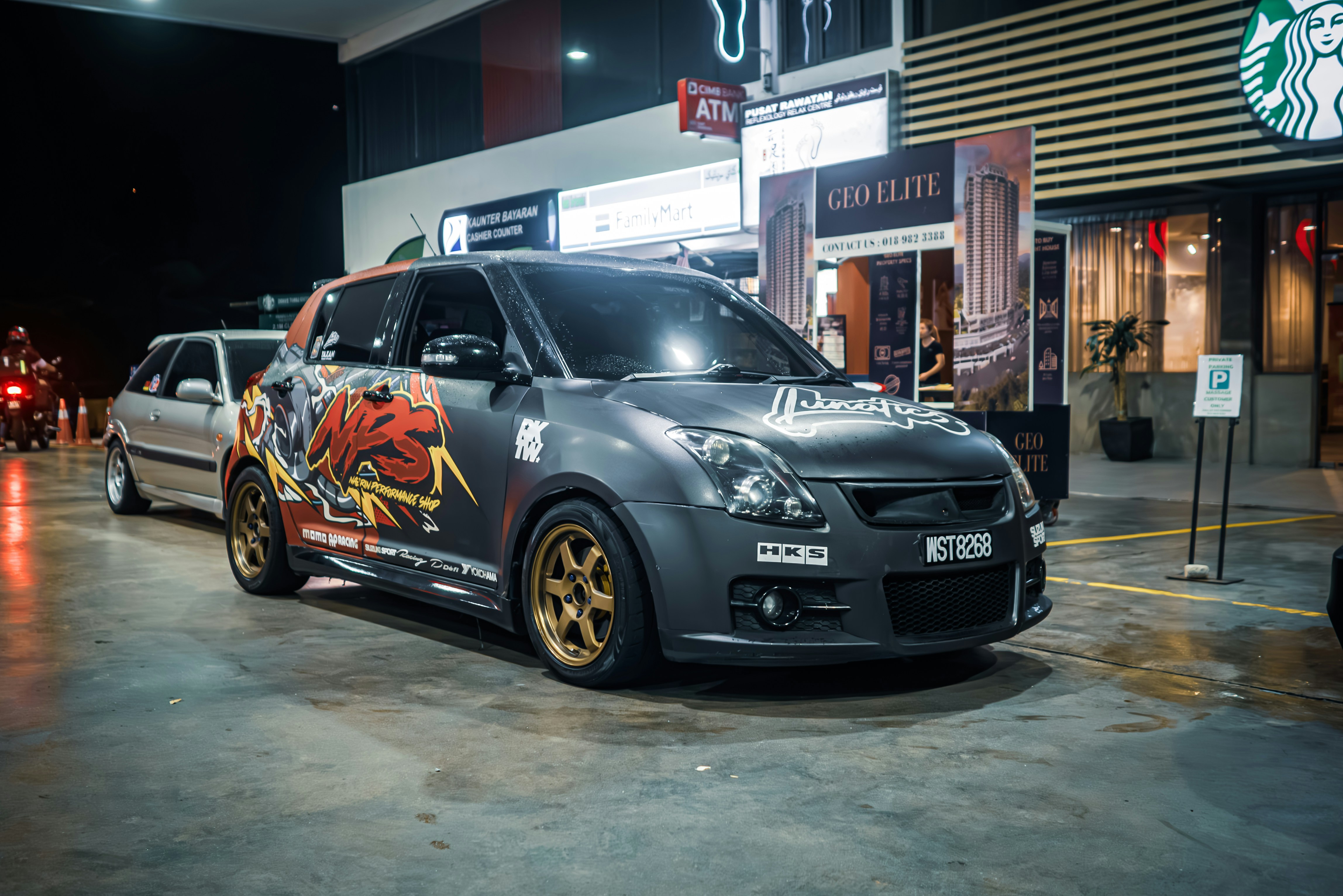 Dragon-Wrap at Neon Night: A Gold-Wheel Minivan in a Quiet Service Plaza