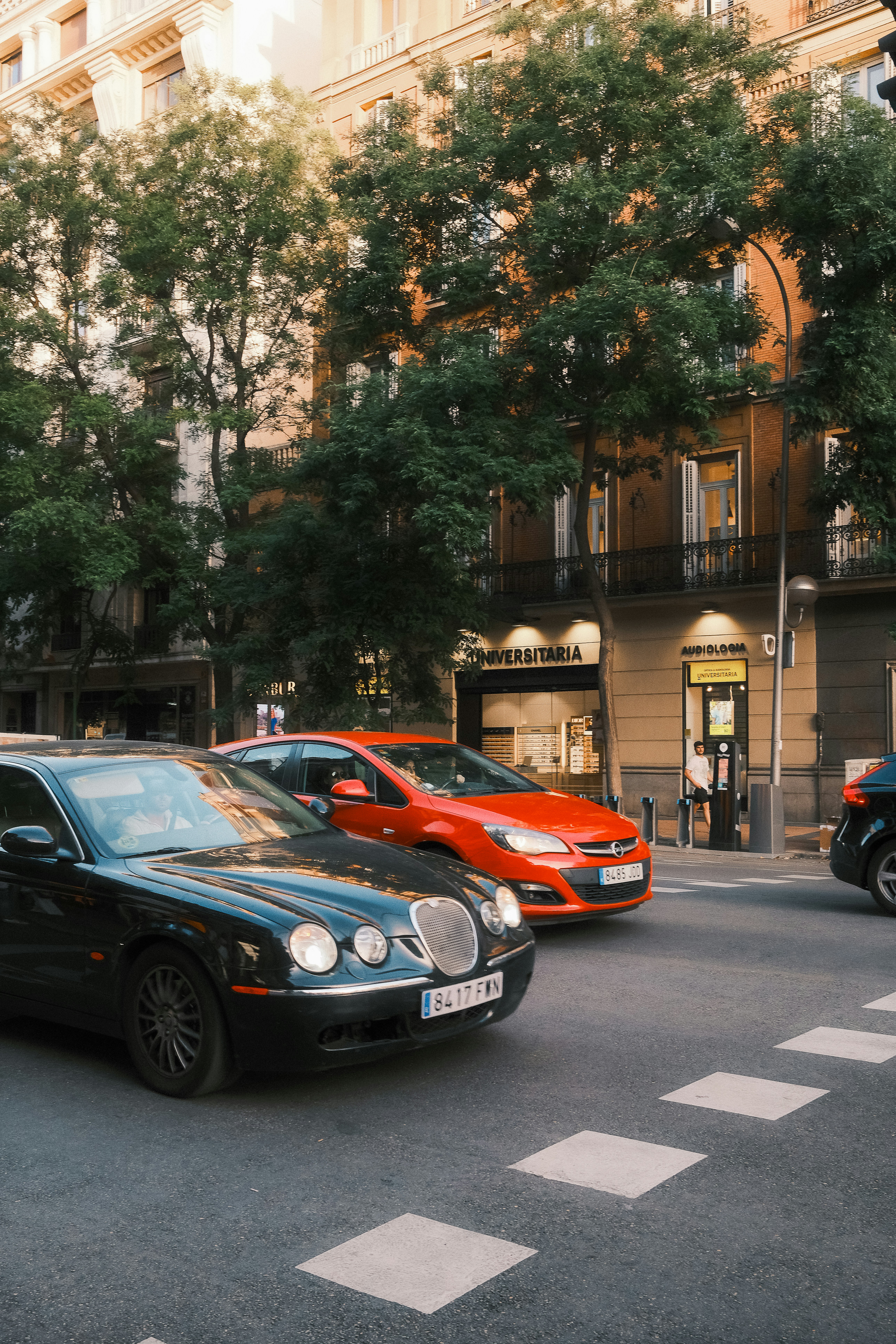 Crimson Car at a Sunlit City Crossing