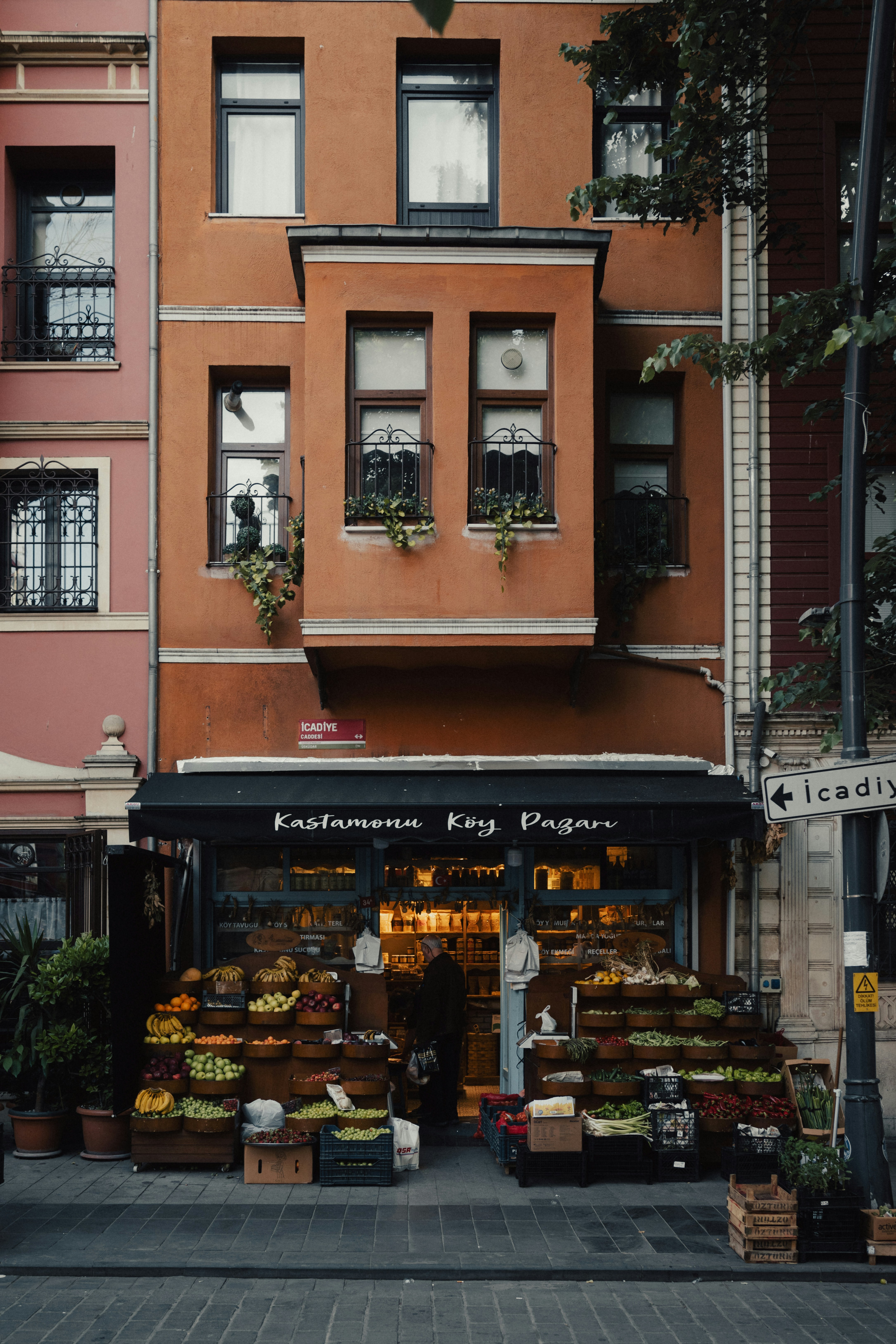 Terracotta Townhouse Market: A Street-Level Fruit Stand under a Blooming Balcony