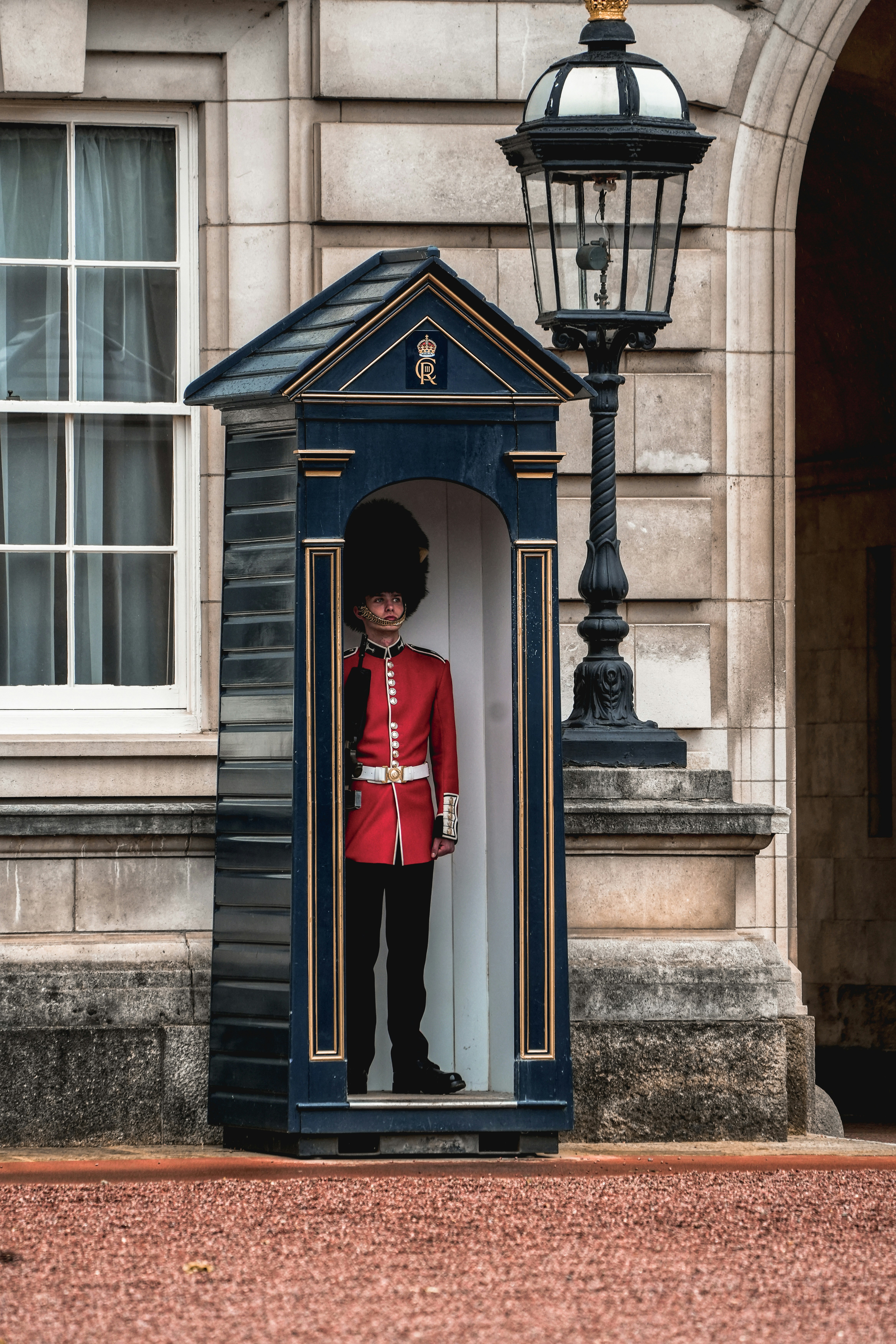 Blue Sentry Booth: A Redcoat Guard Against a Historic Stone Facade