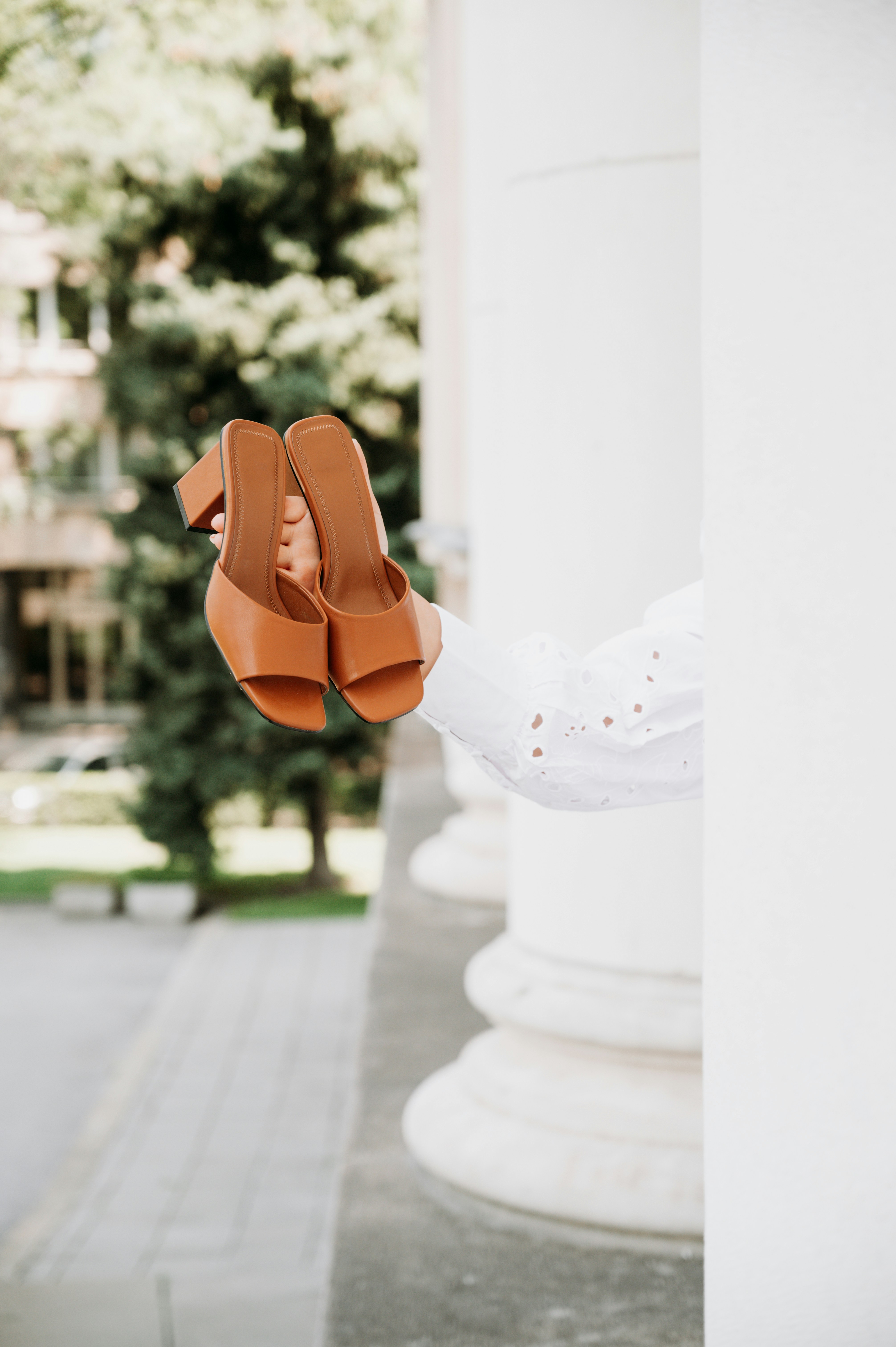 a woman is holding a pair of brown sandals