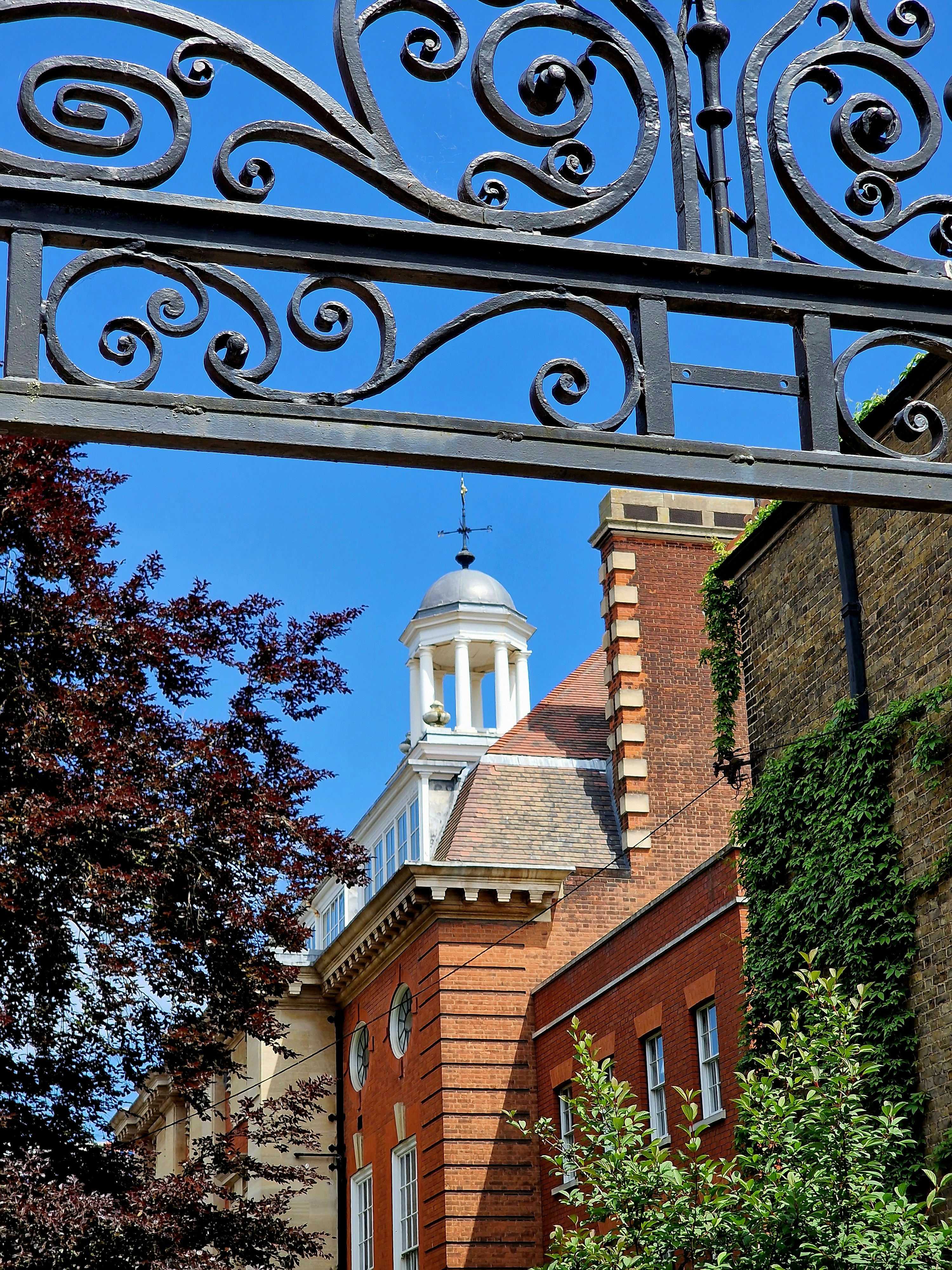 Ironwork Framing a Cupola Above Brick Facade Under Cerulean Sky