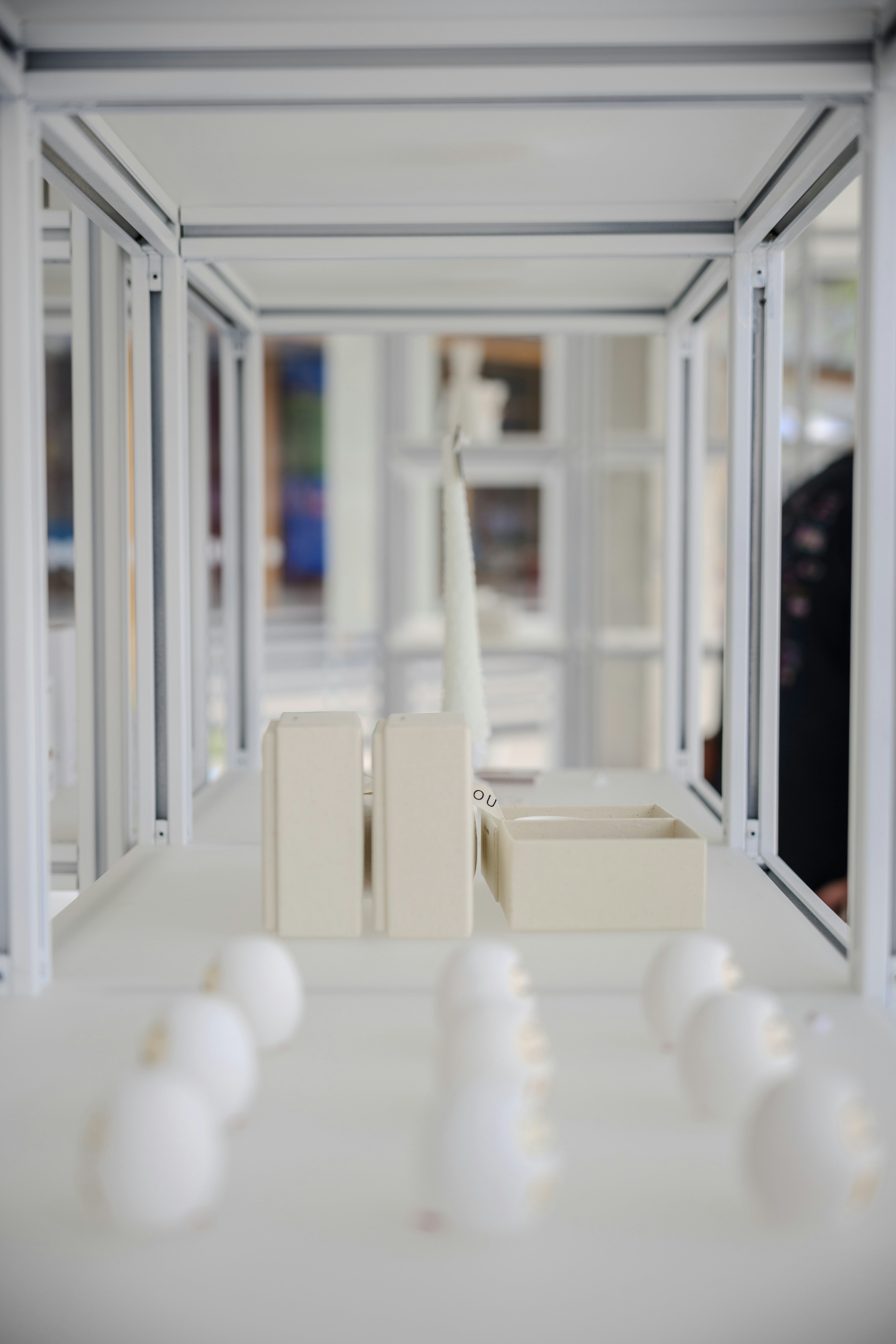 Soft-focused showroom of white modular objects framed by glass corridors