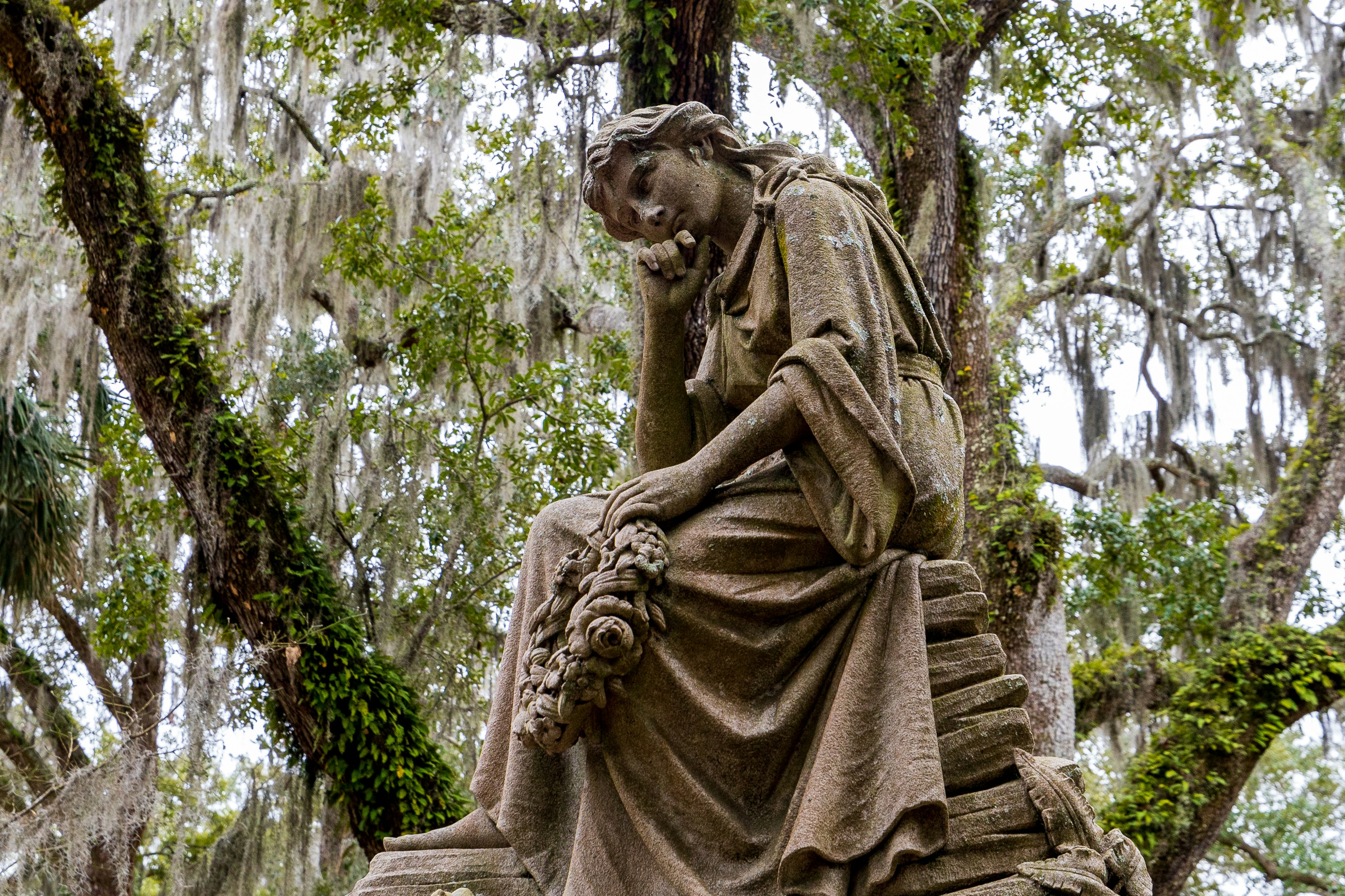 A Silent Stance: Stone Figure Among Moss-Draped Oaks