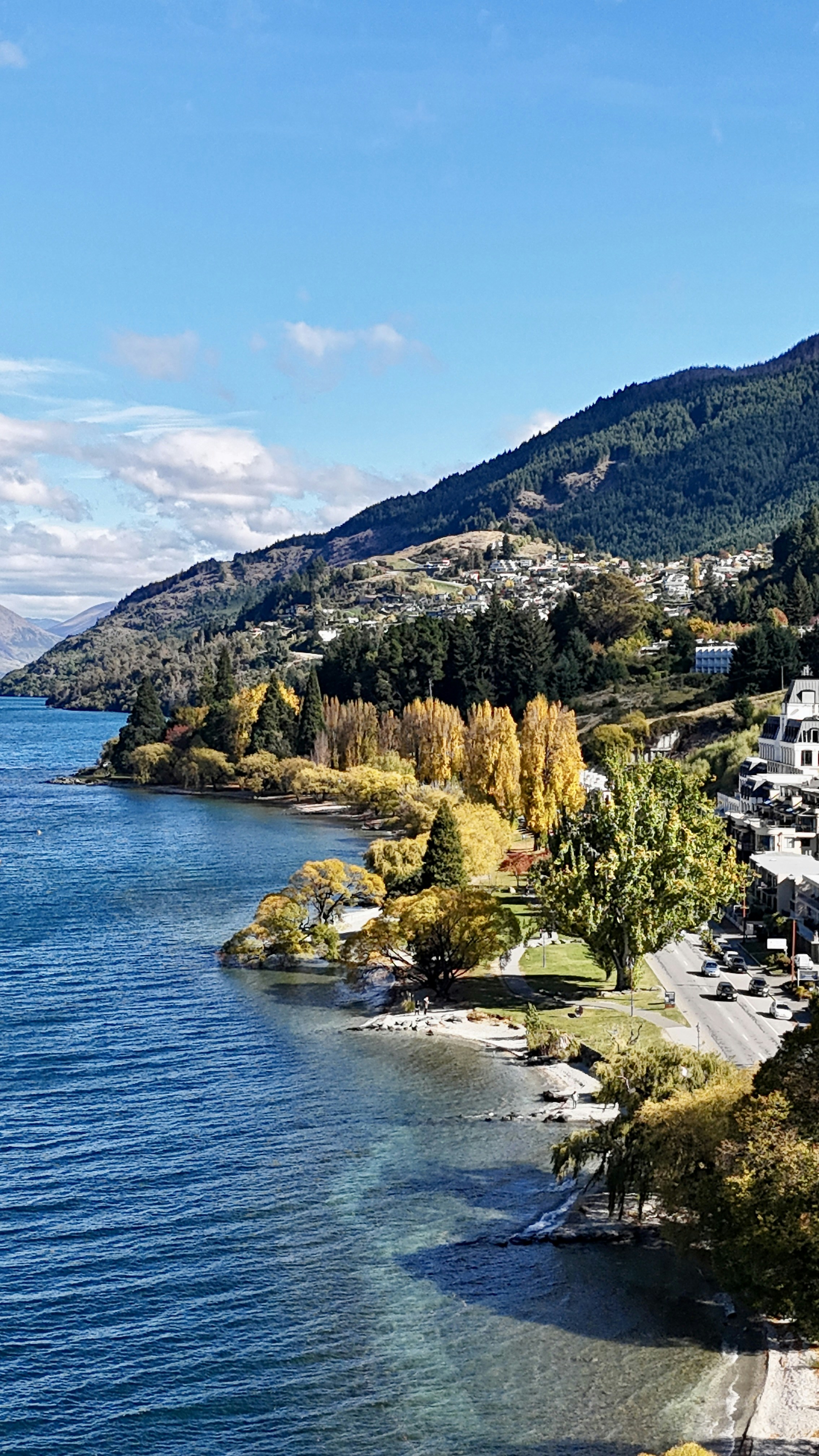 The photo captures the breathtaking beauty of Queenstown, New Zealand, showcasing a scenic view of the town nestled beside a sparkling body of water, framed by majestic mountains. This picturesque scene highlights the perfect blend of natural splendor and vibrant urban life that Queenstown offers. Ideal for travel enthusiasts and nature lovers, the image encapsulates the stunning landscapes and dynamic atmosphere of one of New Zealand's most popular destinations. This captivating visual of Queenstown's unique charm makes it a must-visit location for anyone seeking adventure and natural beauty. | a scenic view of a town and a body of water