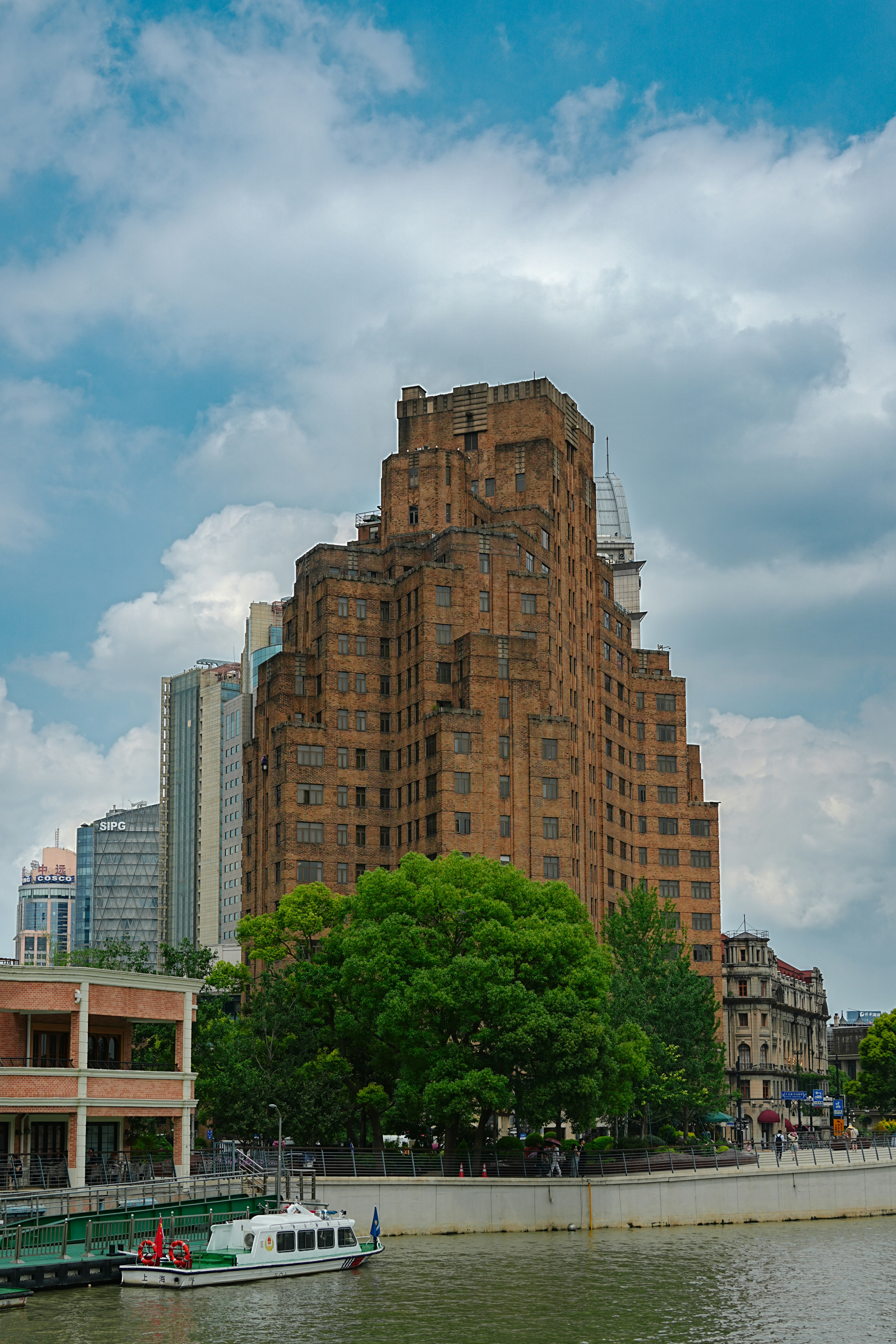 Riverside Terraced Brick Tower Framed by a Green Canopy