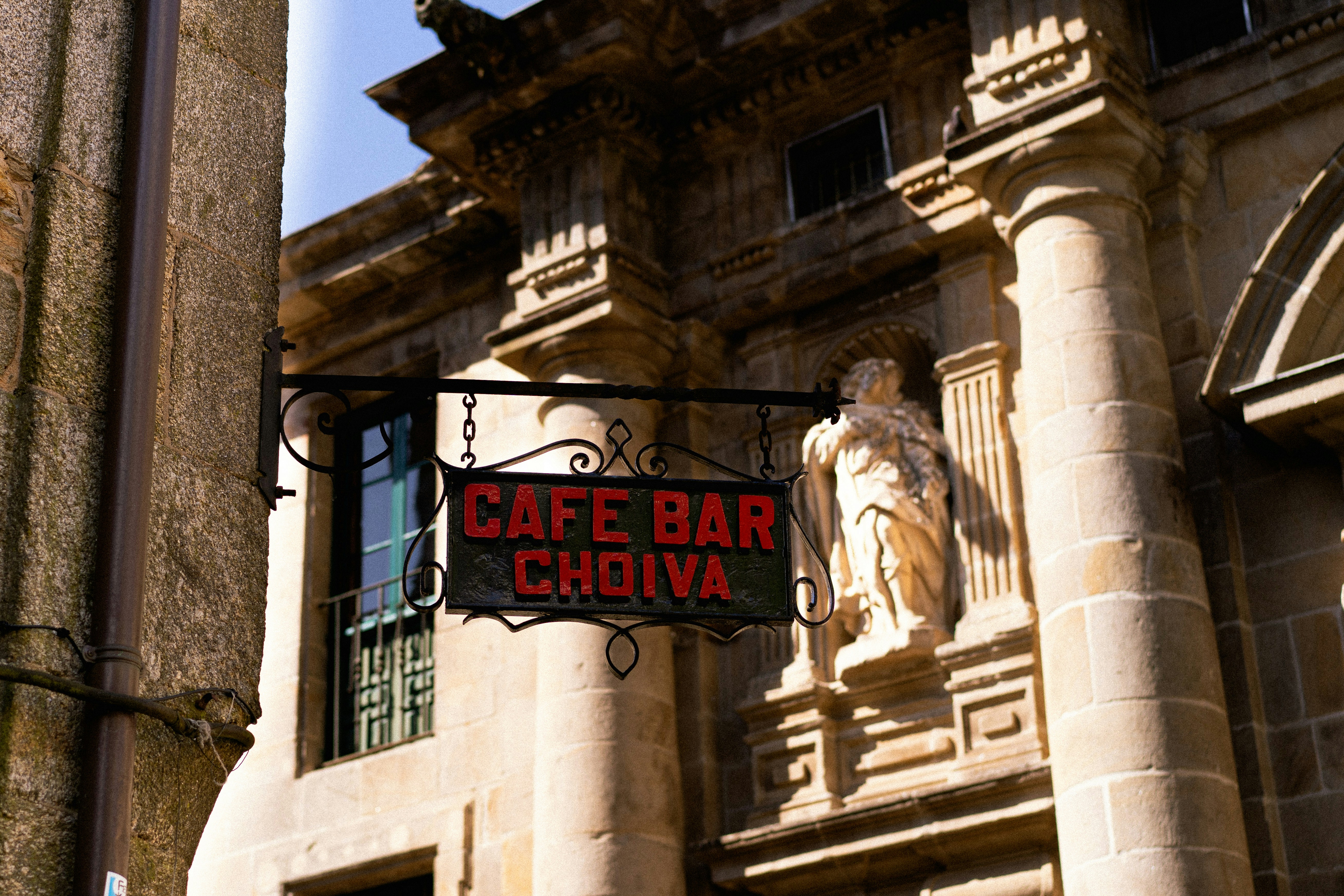 Crimson Café Bar Sign Framed by Historic Stone Columns