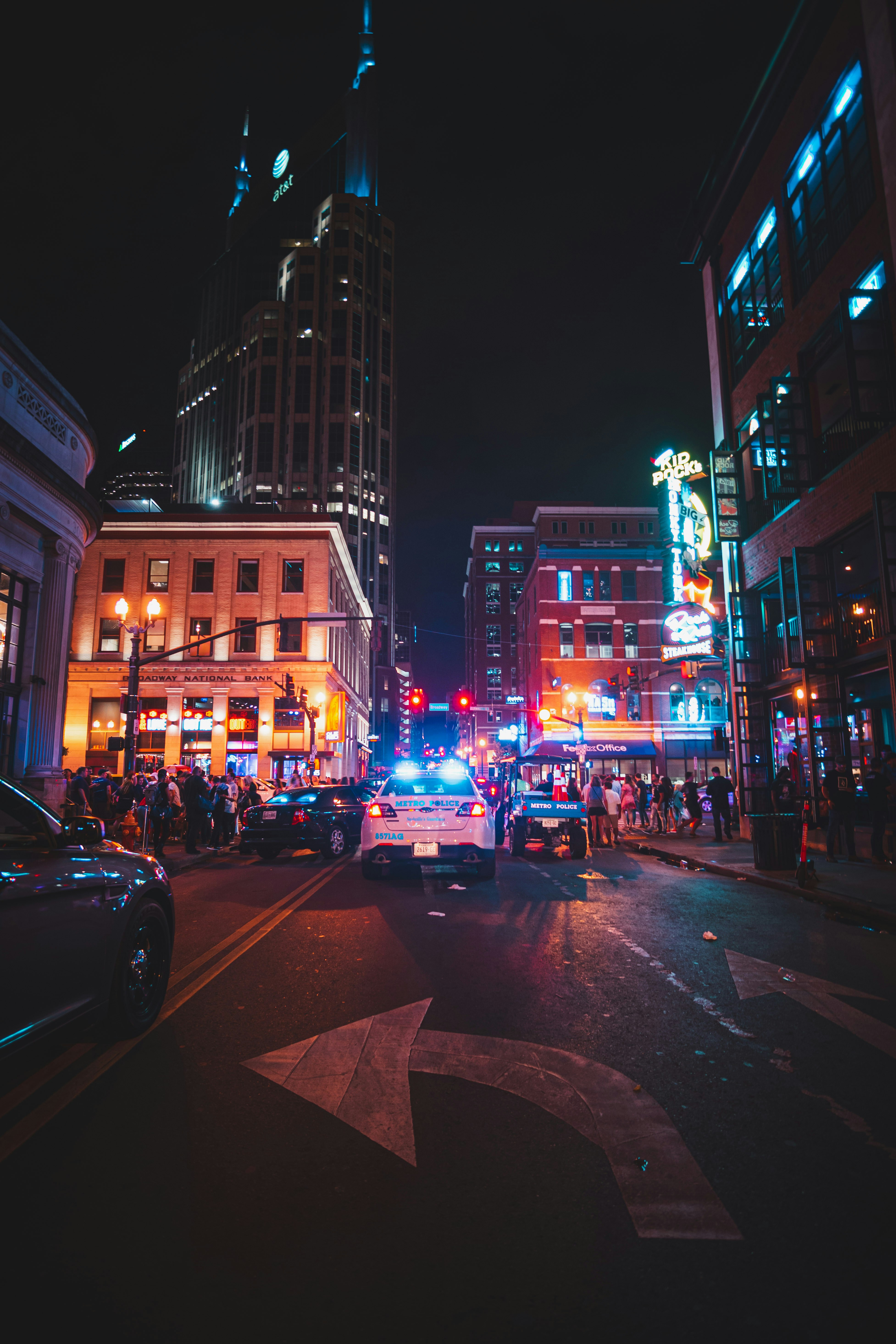 A busy city street at night with cars parked on the side of the road ...