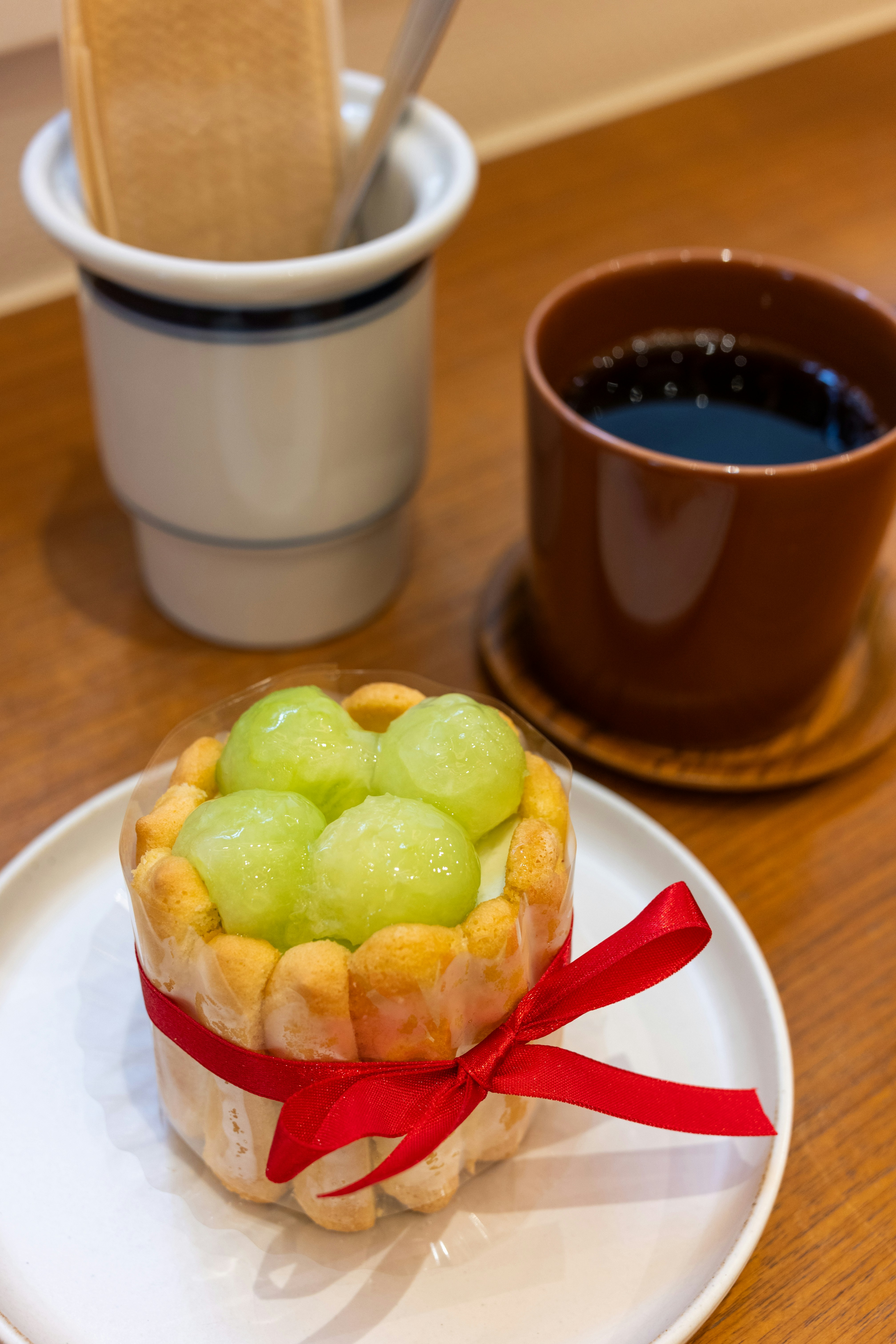 Green-topped Petit Gateau with Red Ribbon, Beside a Mug of Coffee