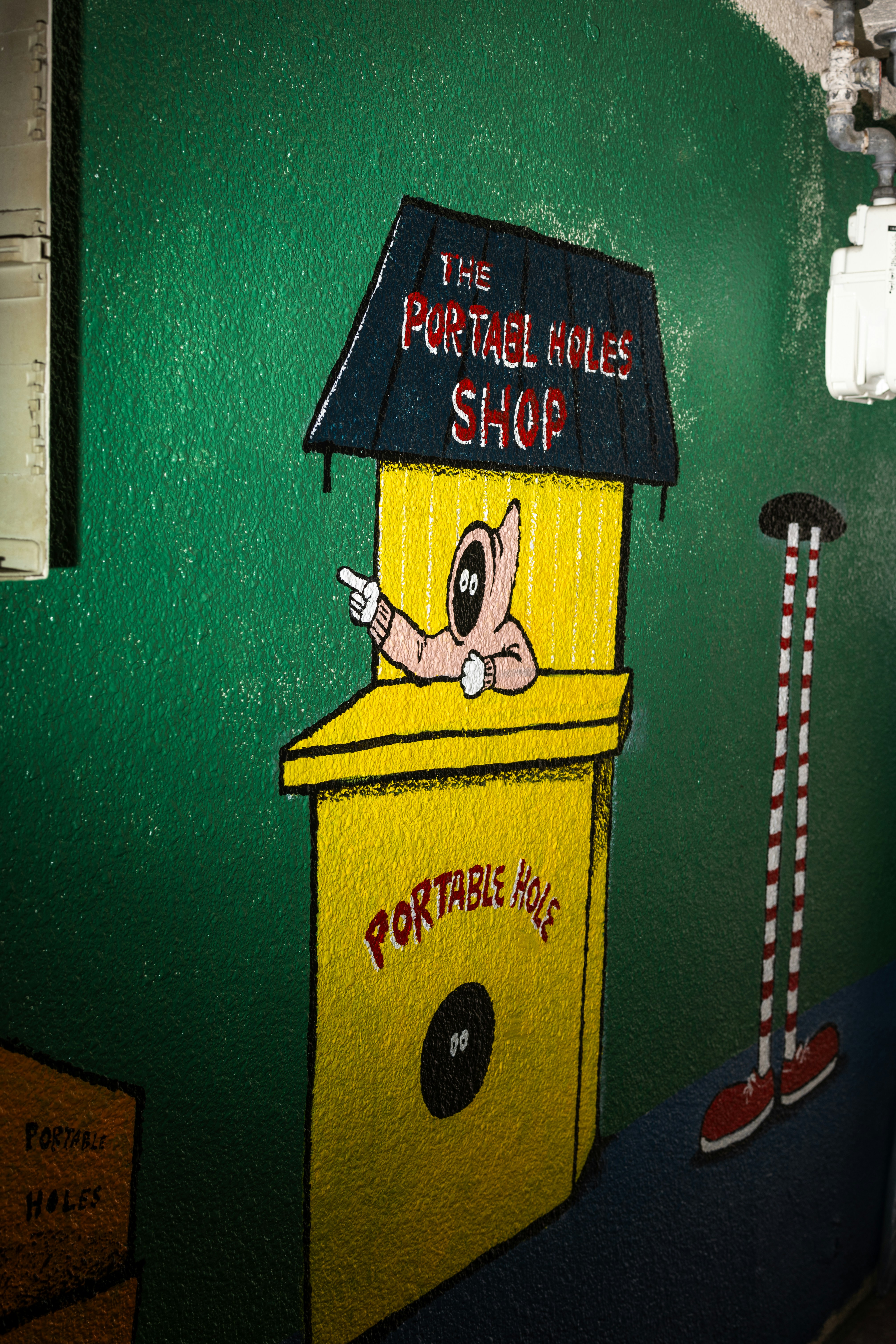 The Portable Holes Shop: Cartoon Mascot Peeking From a Bright Yellow Portal on Emerald Wall