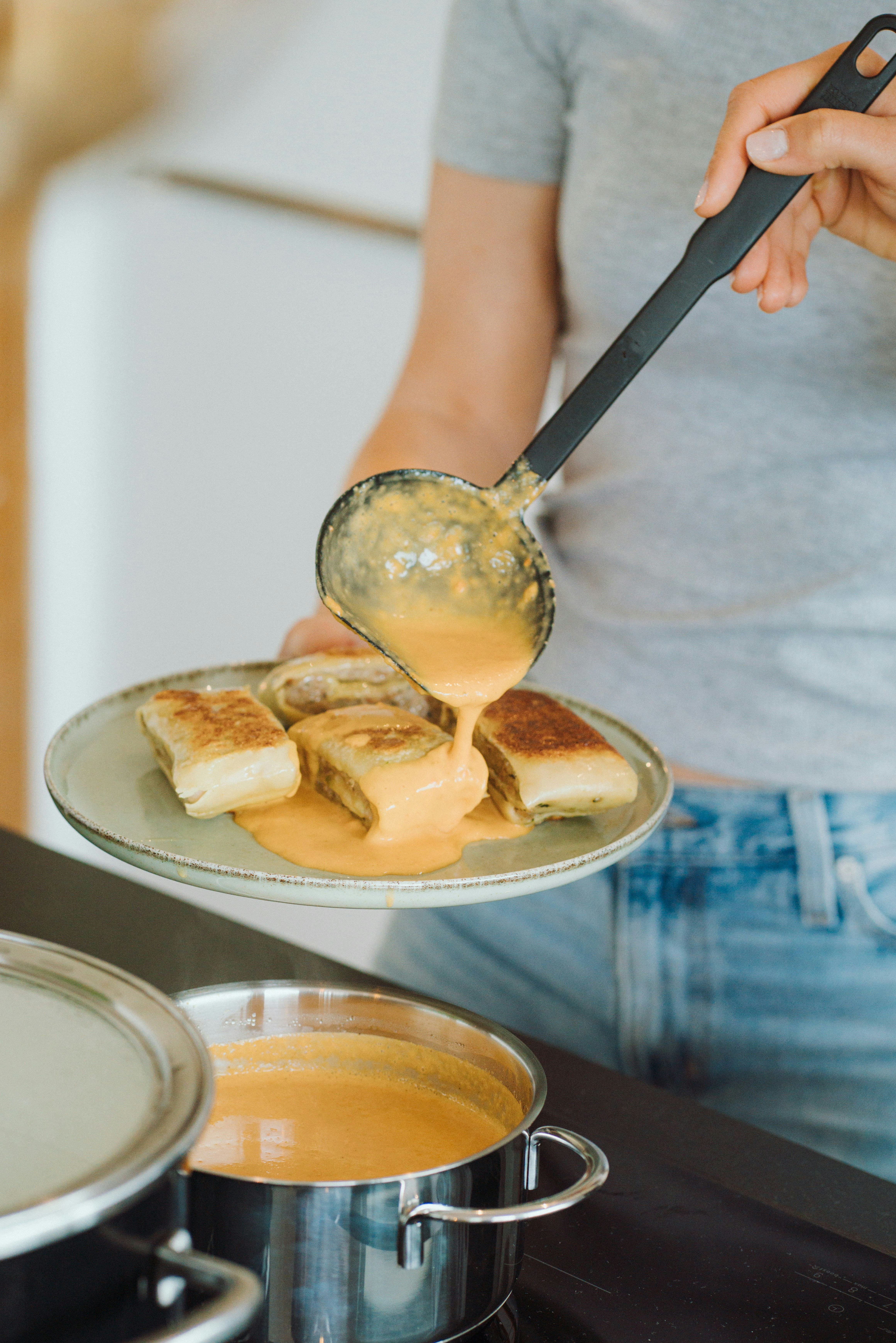 A woman is spooning some food on a plate photo – Free Food Image on ...