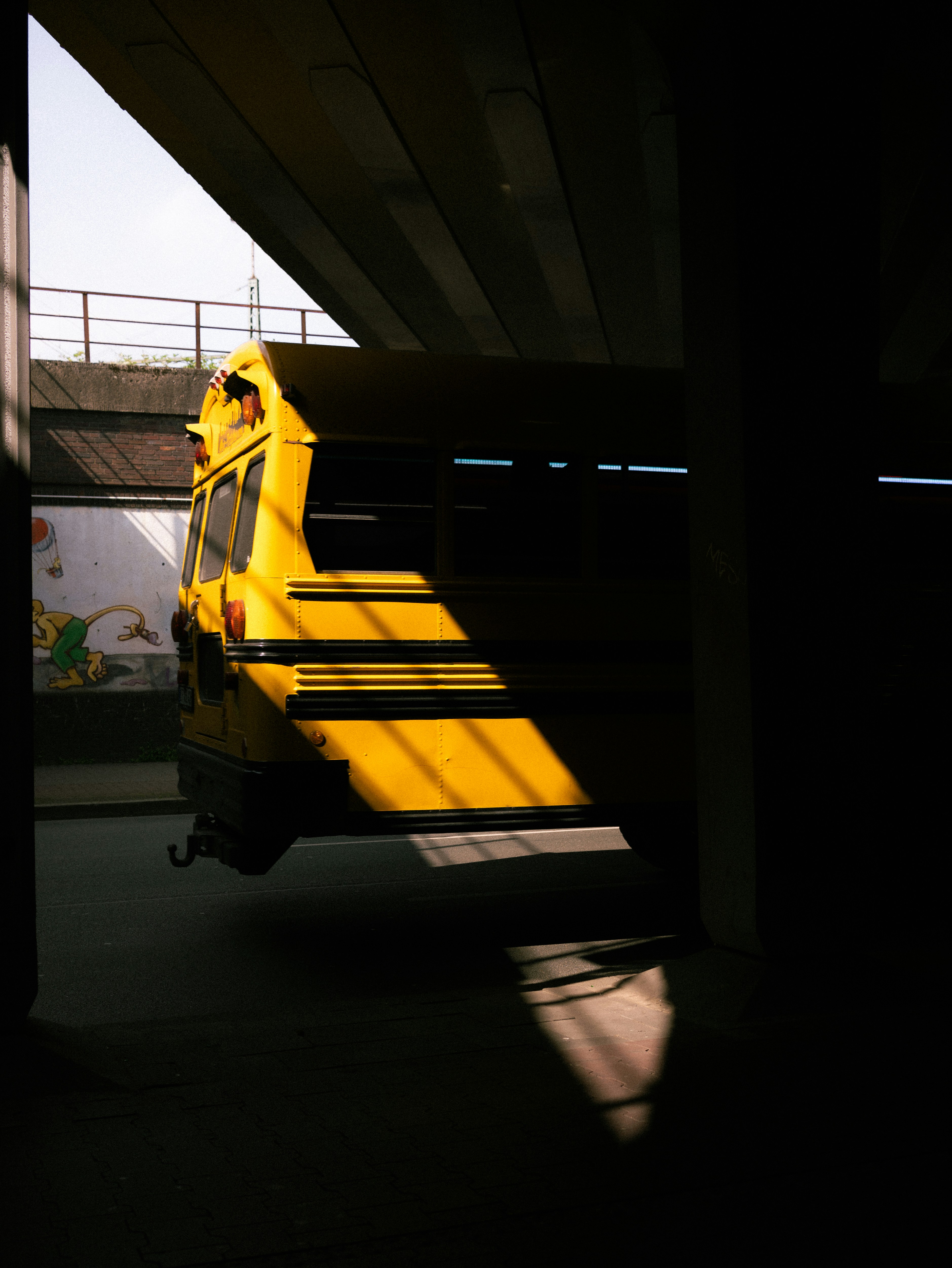 A yellow bus is parked under a bridge photo – Free Street photography ...