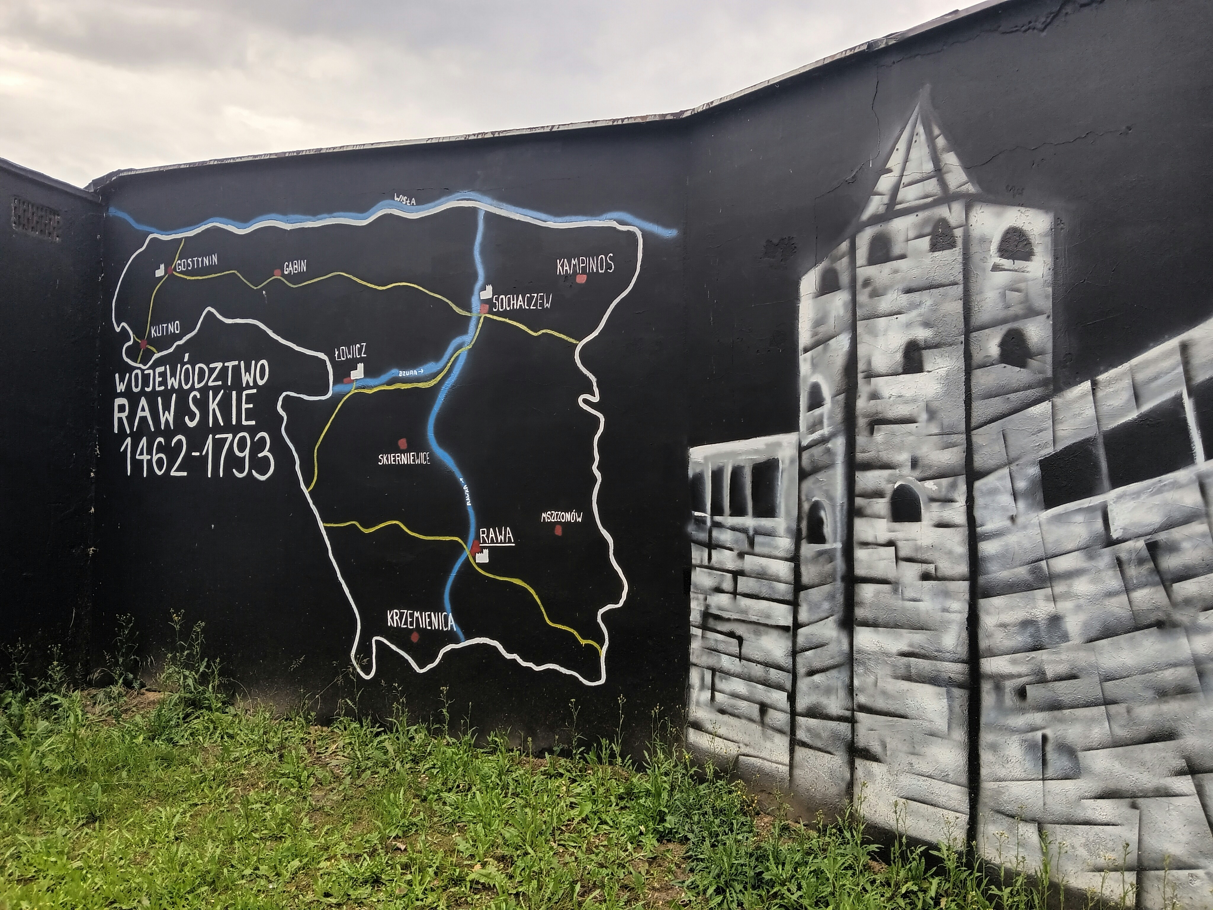 Map and tower illustration on a black wall surrounded by grass.