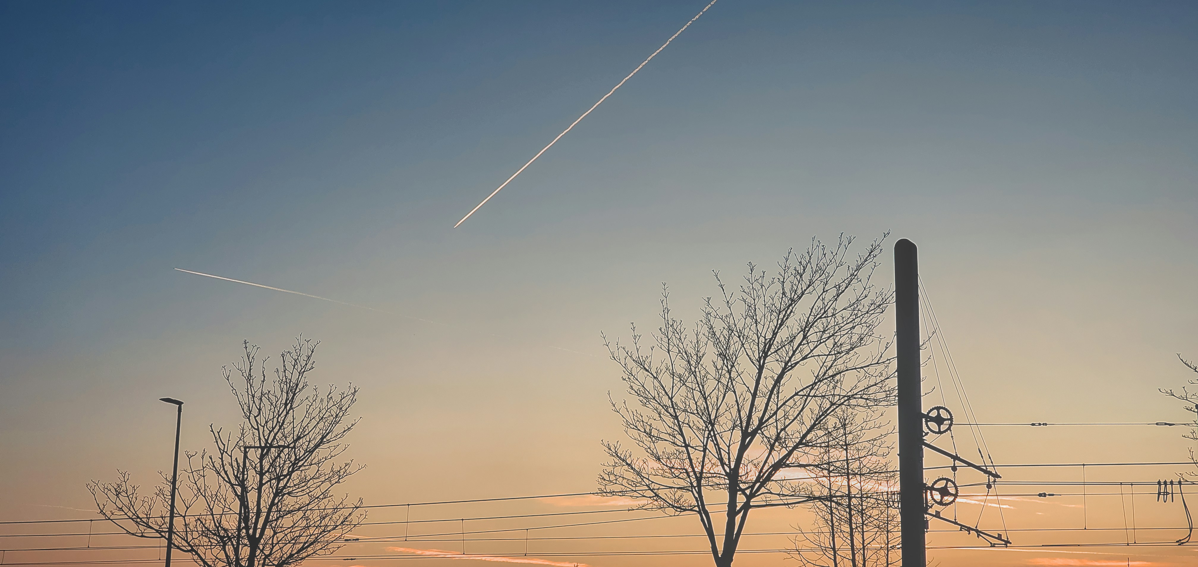 Dusk Between Wires: Contrails Over a Quiet Horizon