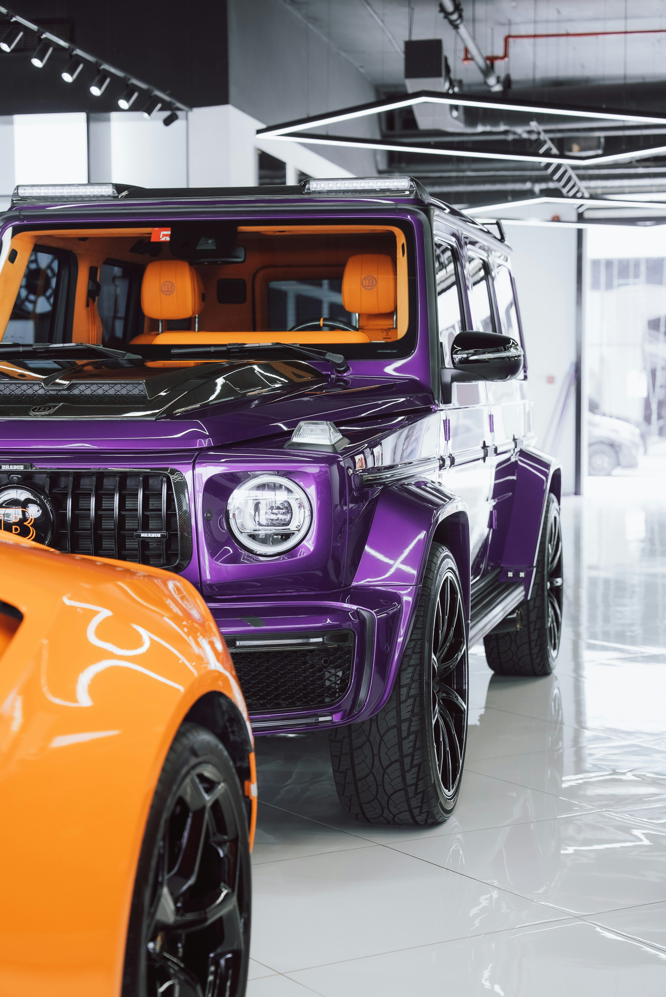 Vibrant purple SUV in a glossy showroom with an orange sports car peeking in