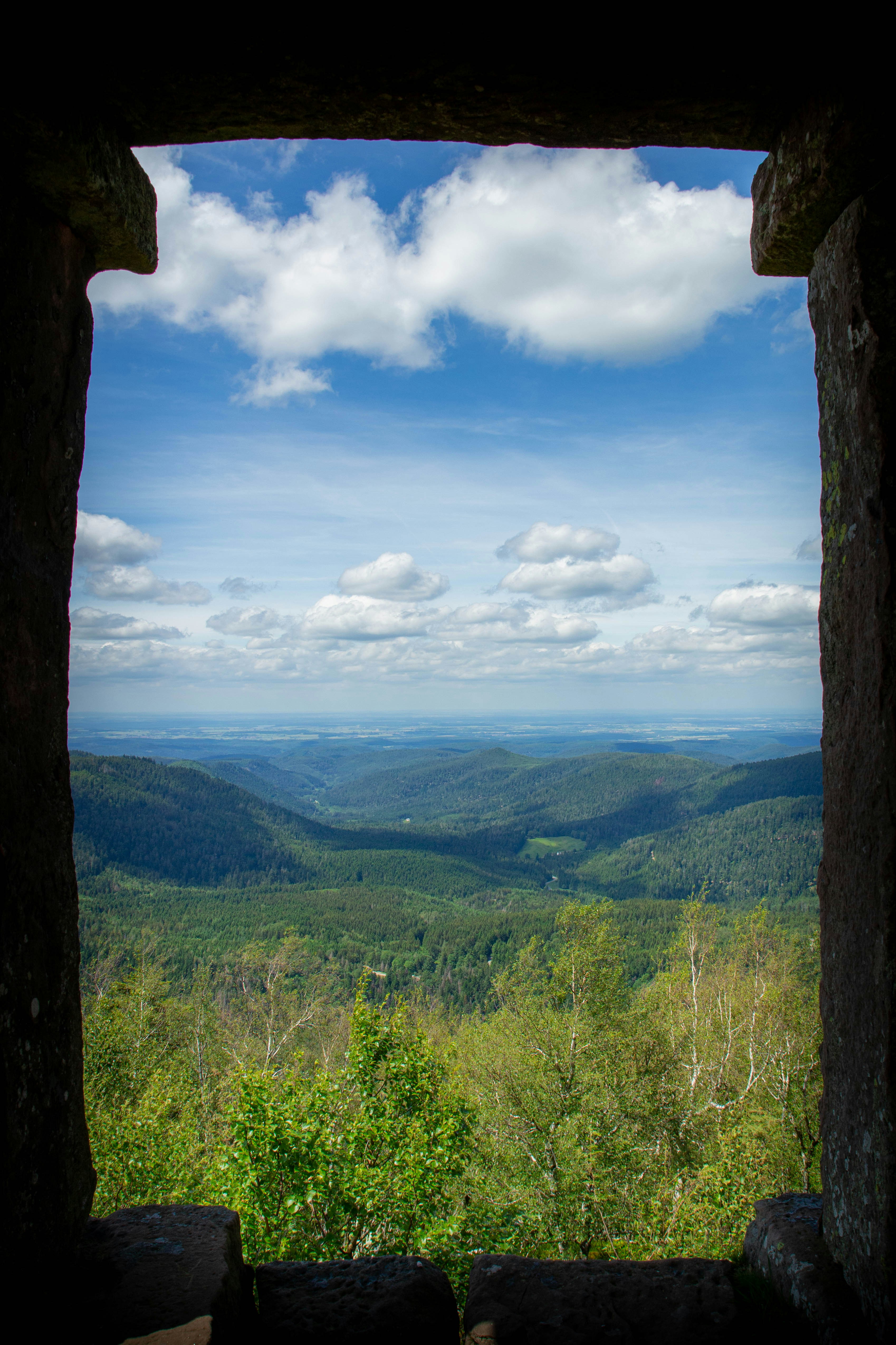 Stone Frame, Open Sky: A Panoramic Vista of Green Ridges Through an Ancient Window