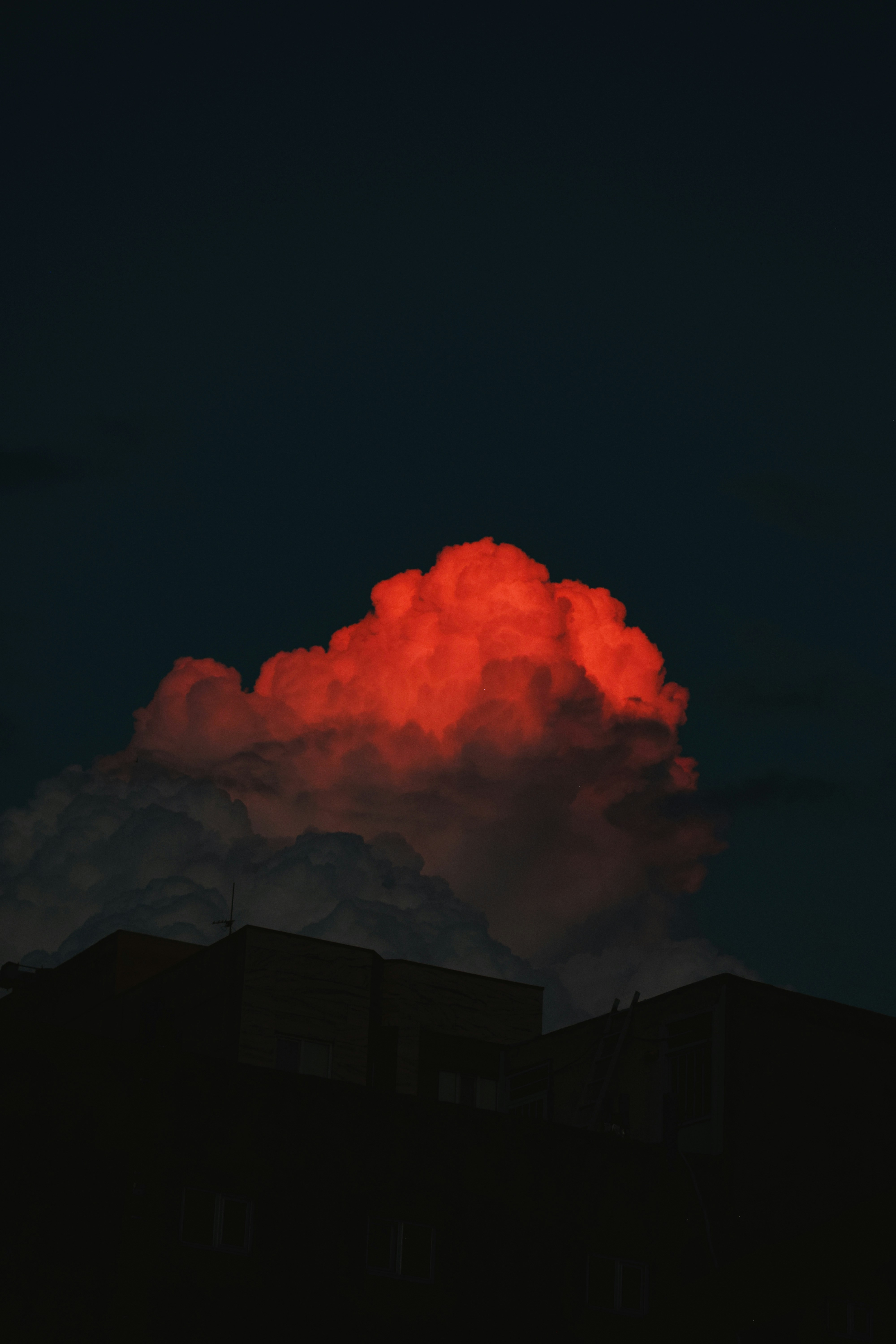 A red cloud is in the sky above a building photo – Free Night Image on ...
