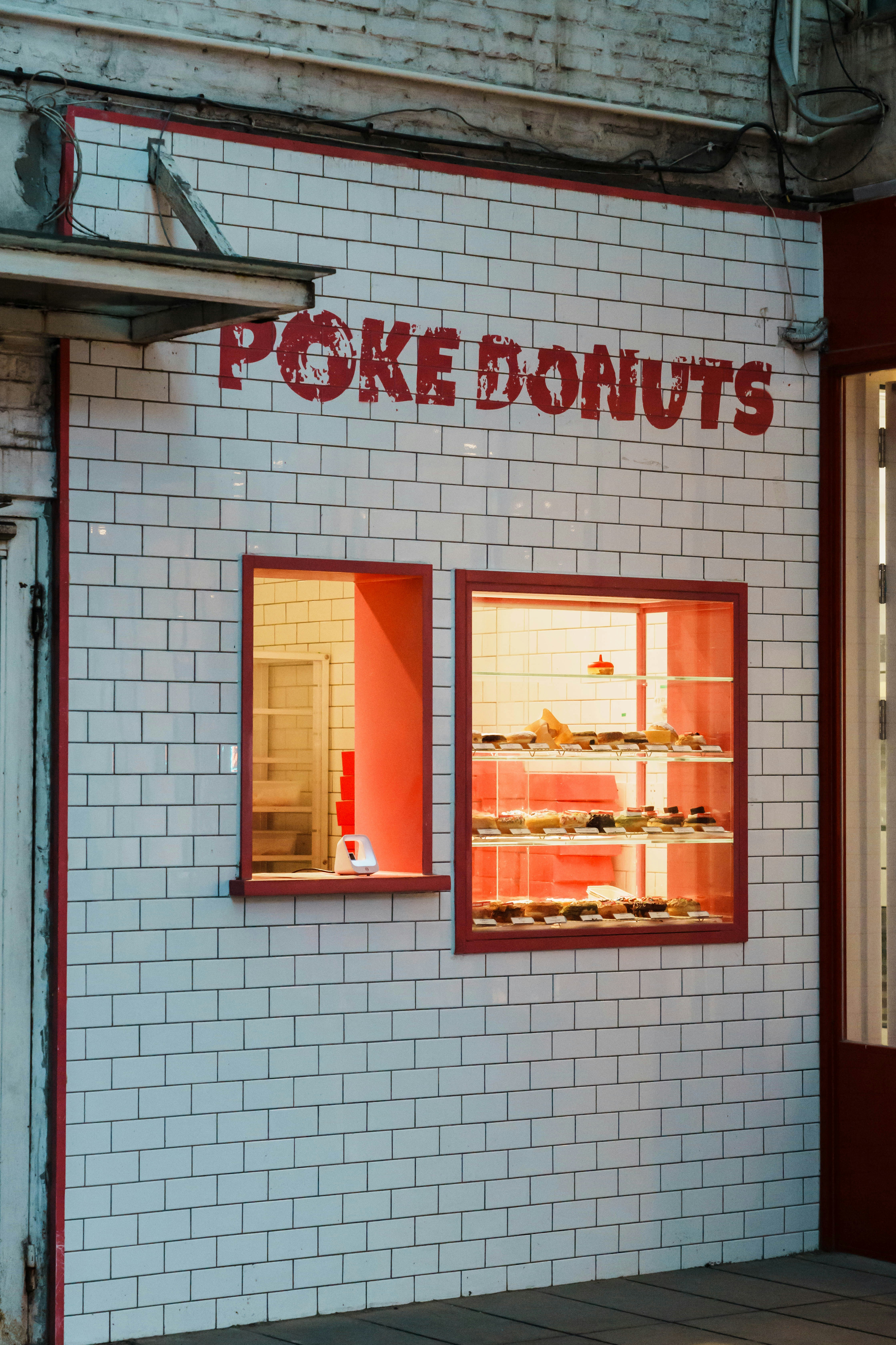 Poke Donuts: Warm Light Through Red-Framed Windows on a Tile Facade