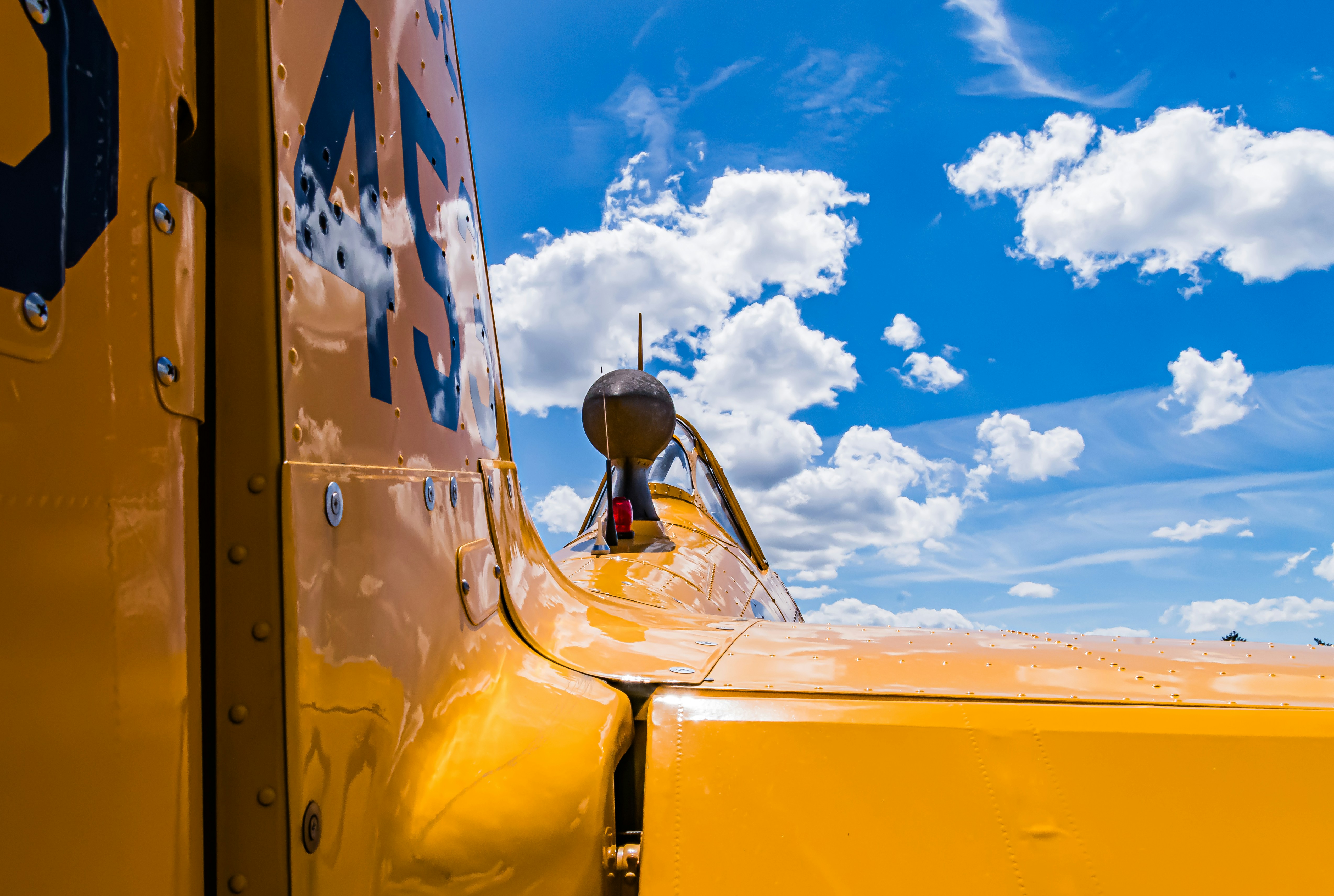 Riveted Gold in a Blue Expanse: close-up on a sunlit yellow aircraft fuselage