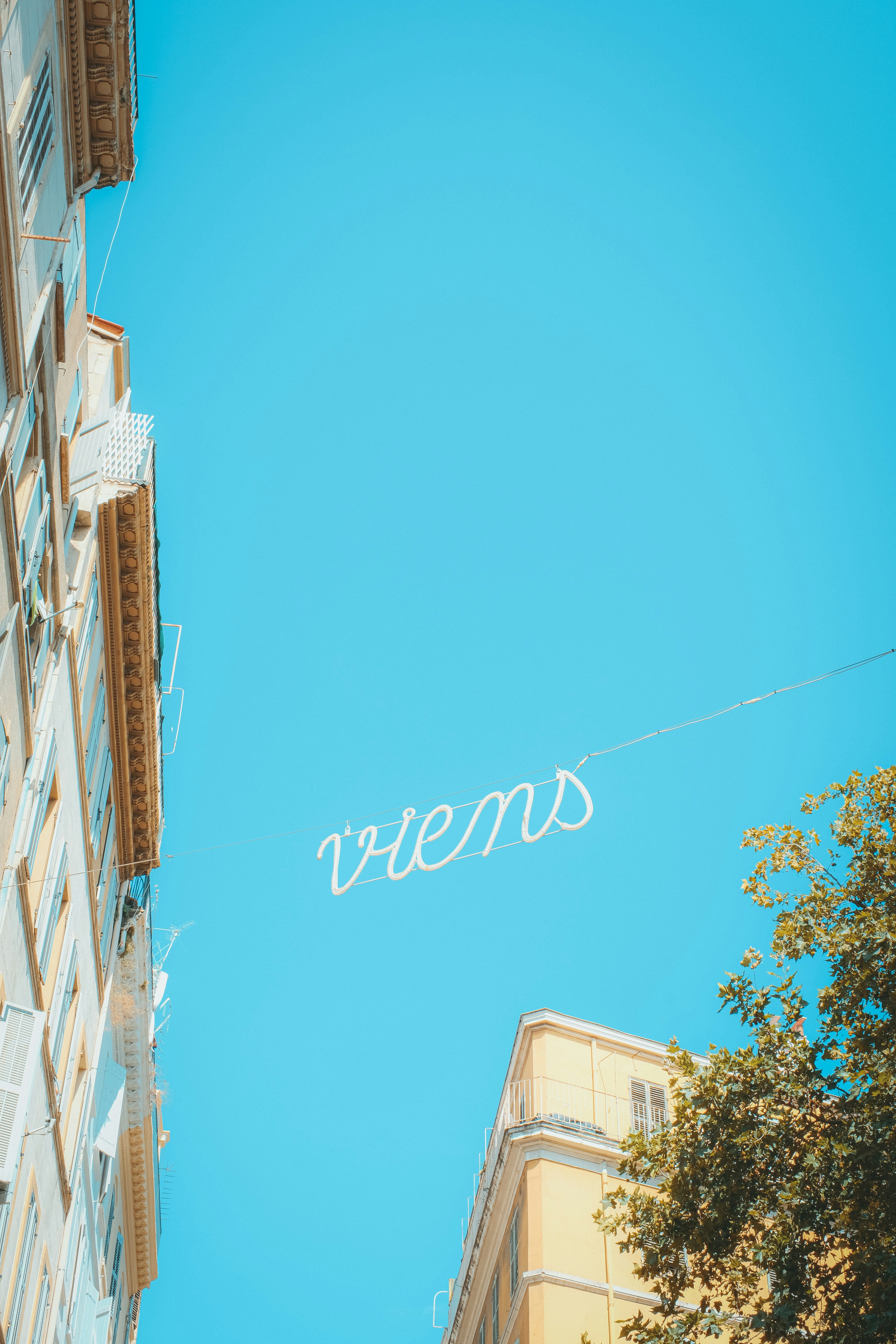 Sky-Washed Script: A Wire-Tied Message Arcing Above Sunlit Facades