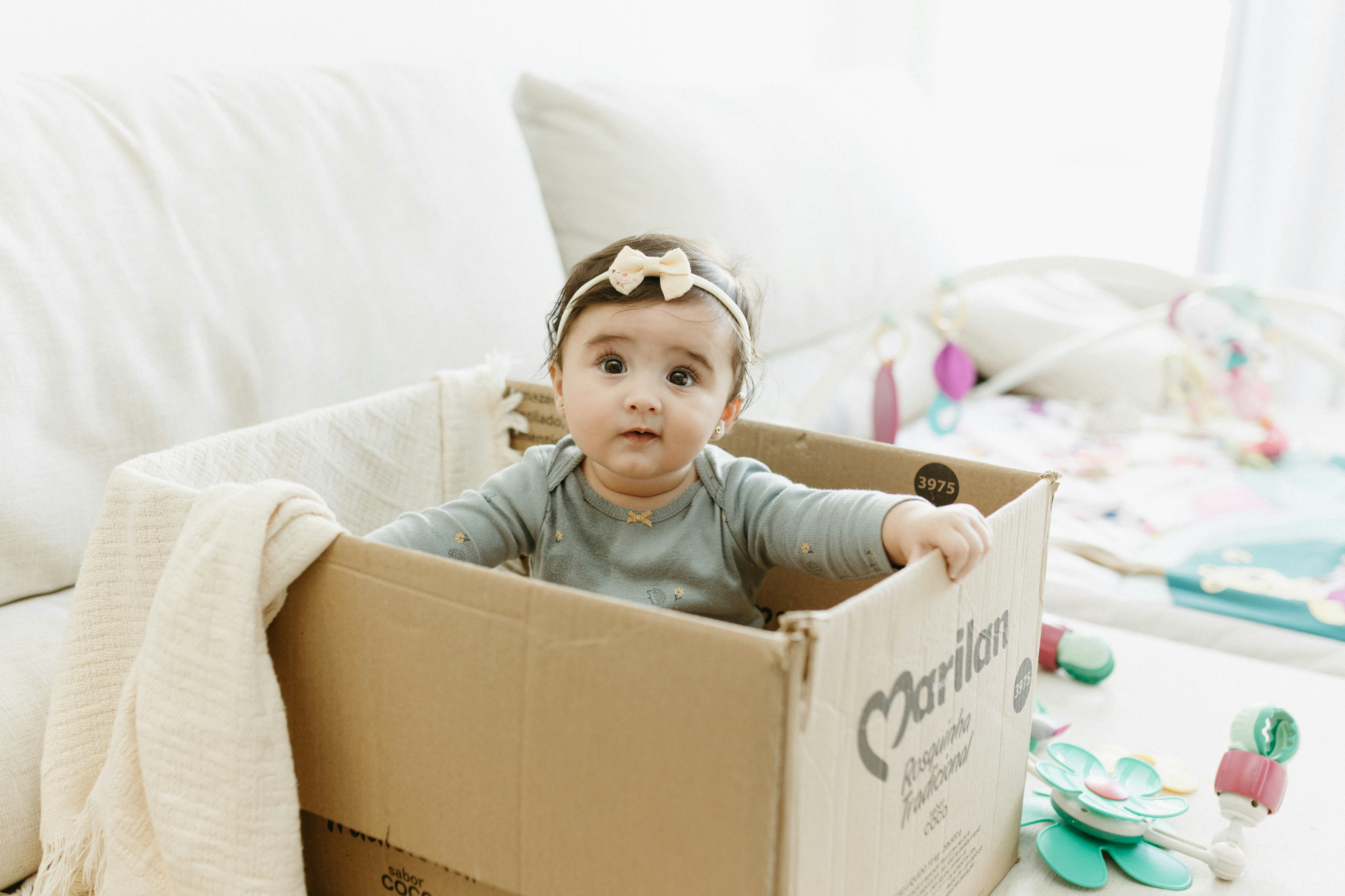 A baby sitting in a cardboard box on the floor photo – Free Baby Image ...