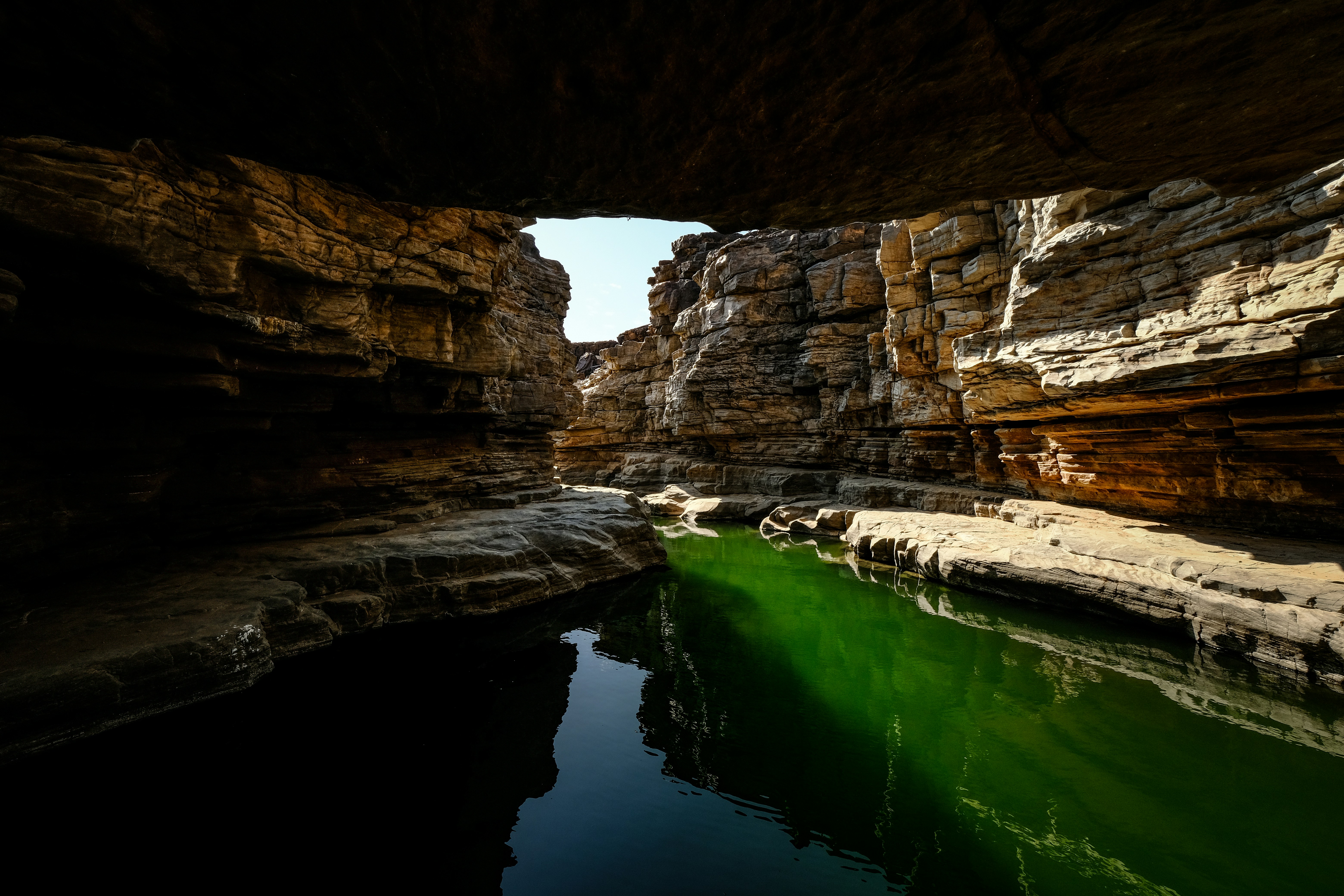 A body of water surrounded by large rocks photo – Free Rock Image on ...