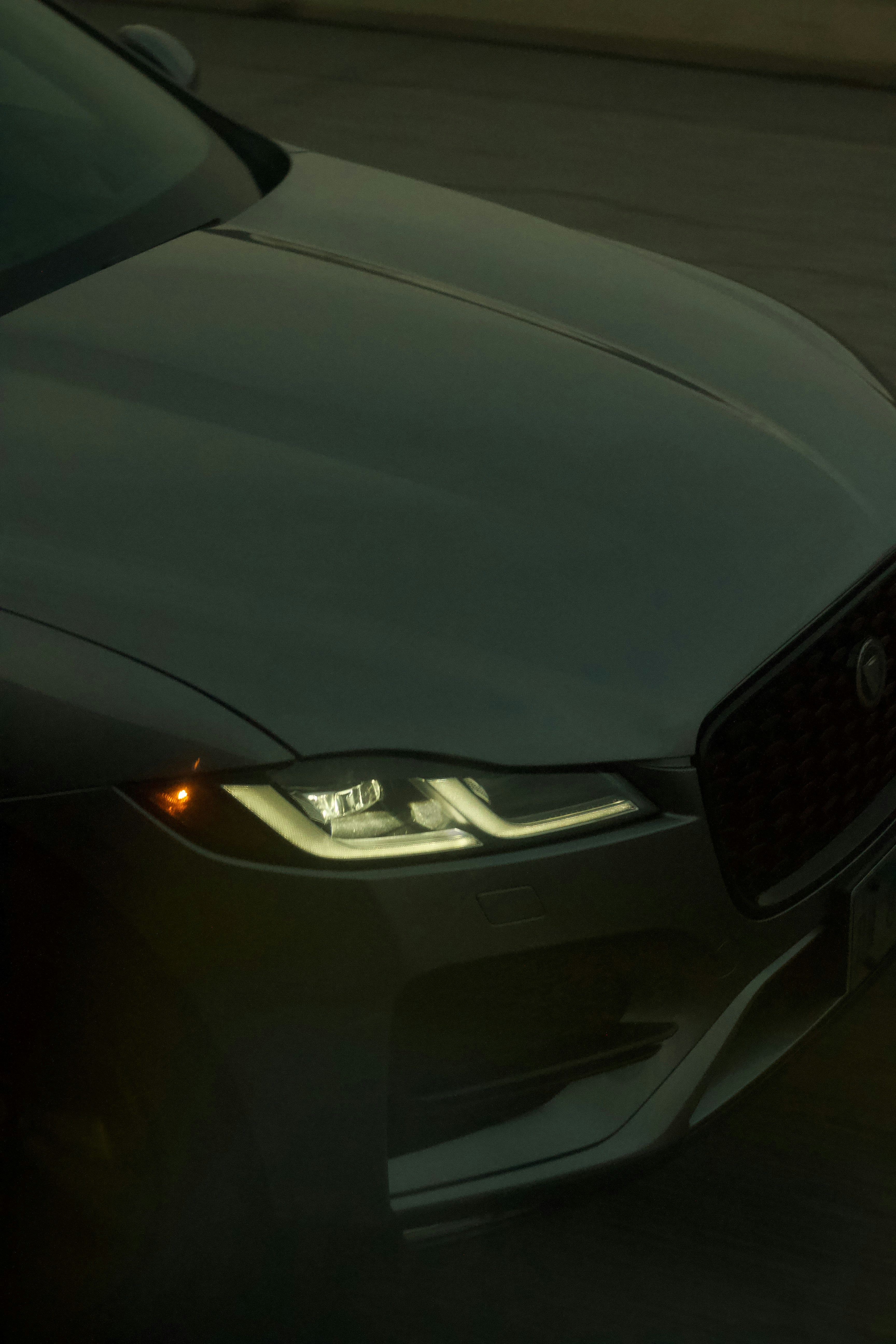 A black car driving down a street next to a building