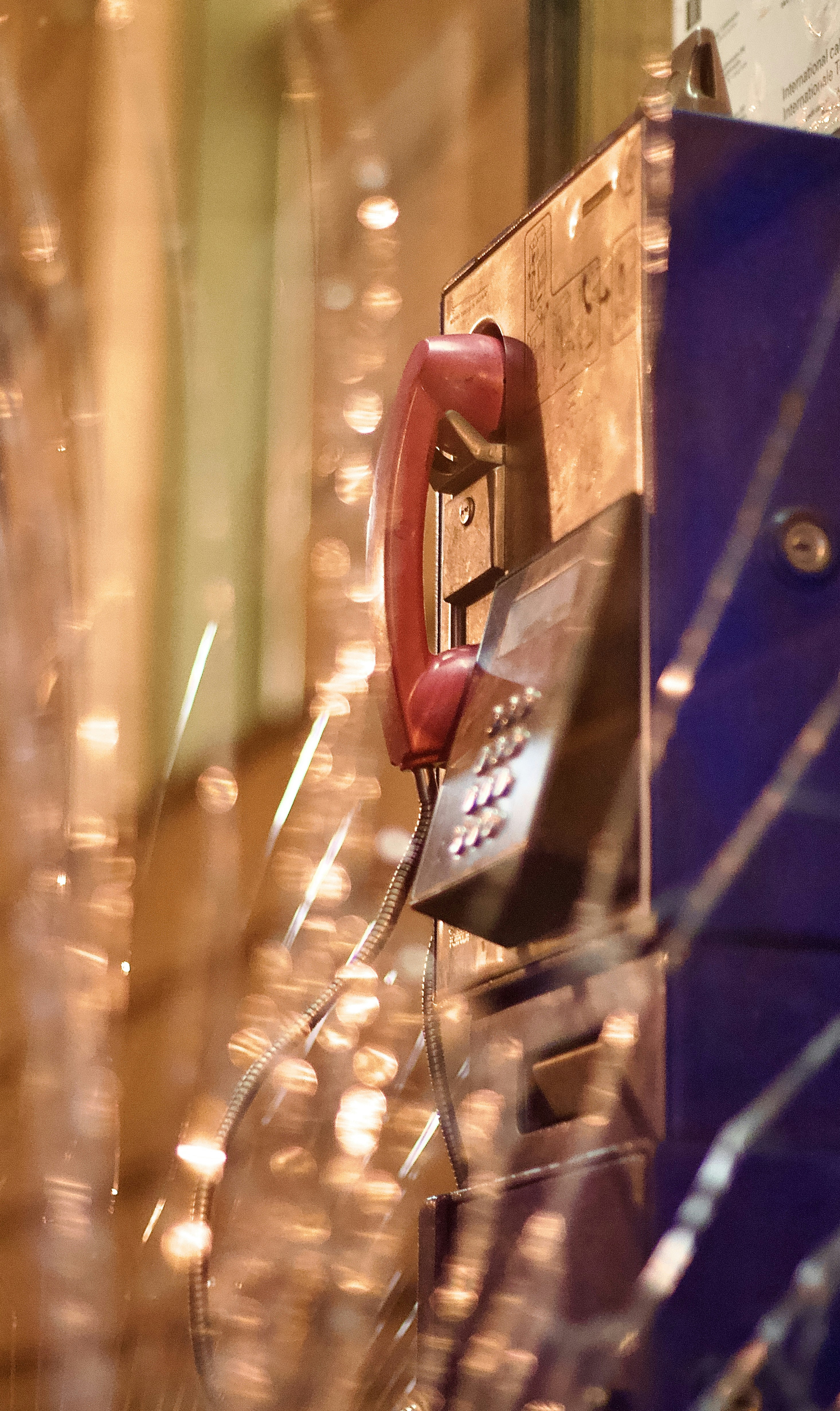 Retro payphone with a red handset framed by soft-focus lights.