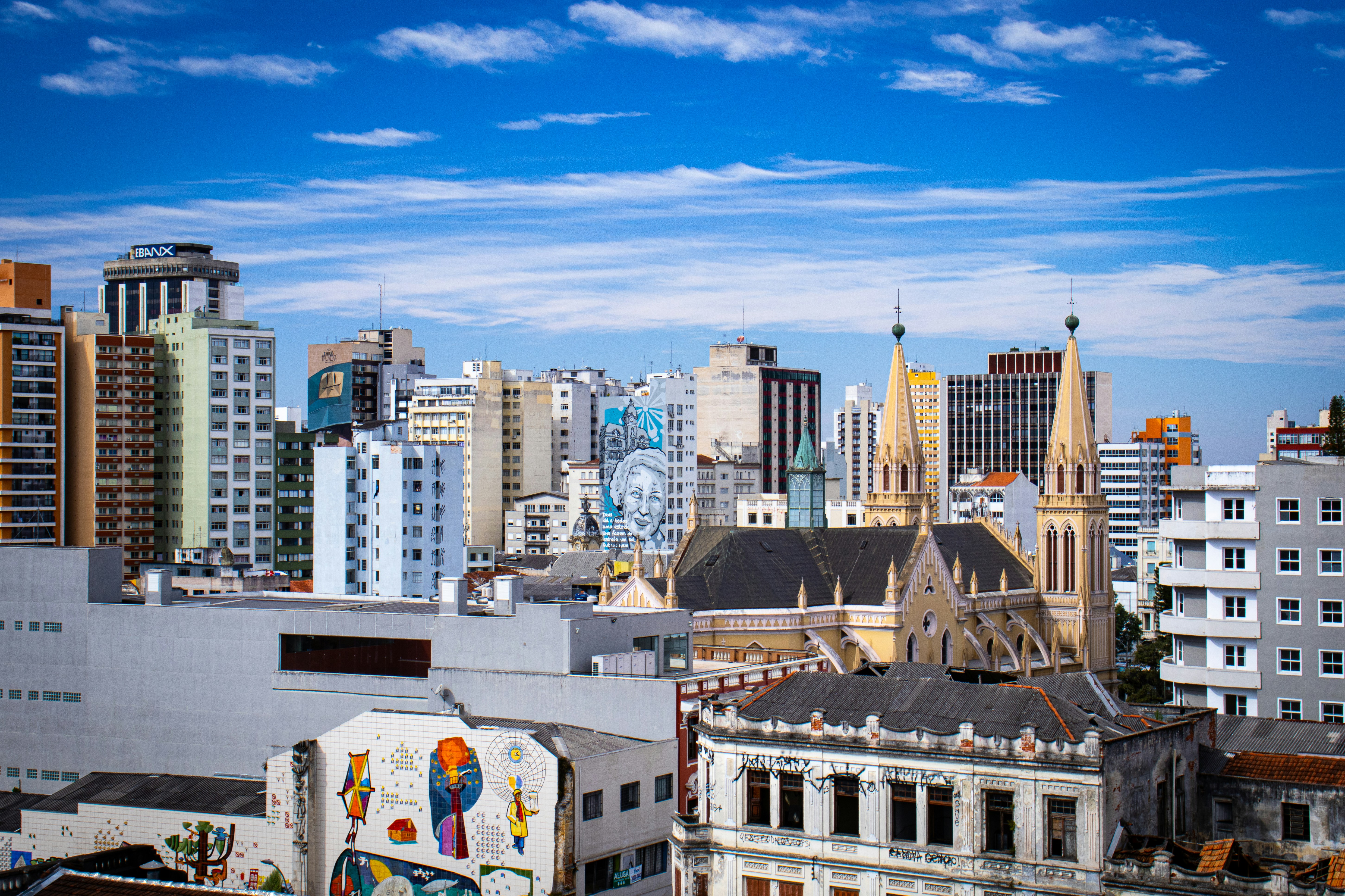 Skyline of a city with historic cathedral and modern buildings under a vivid blue sky.
